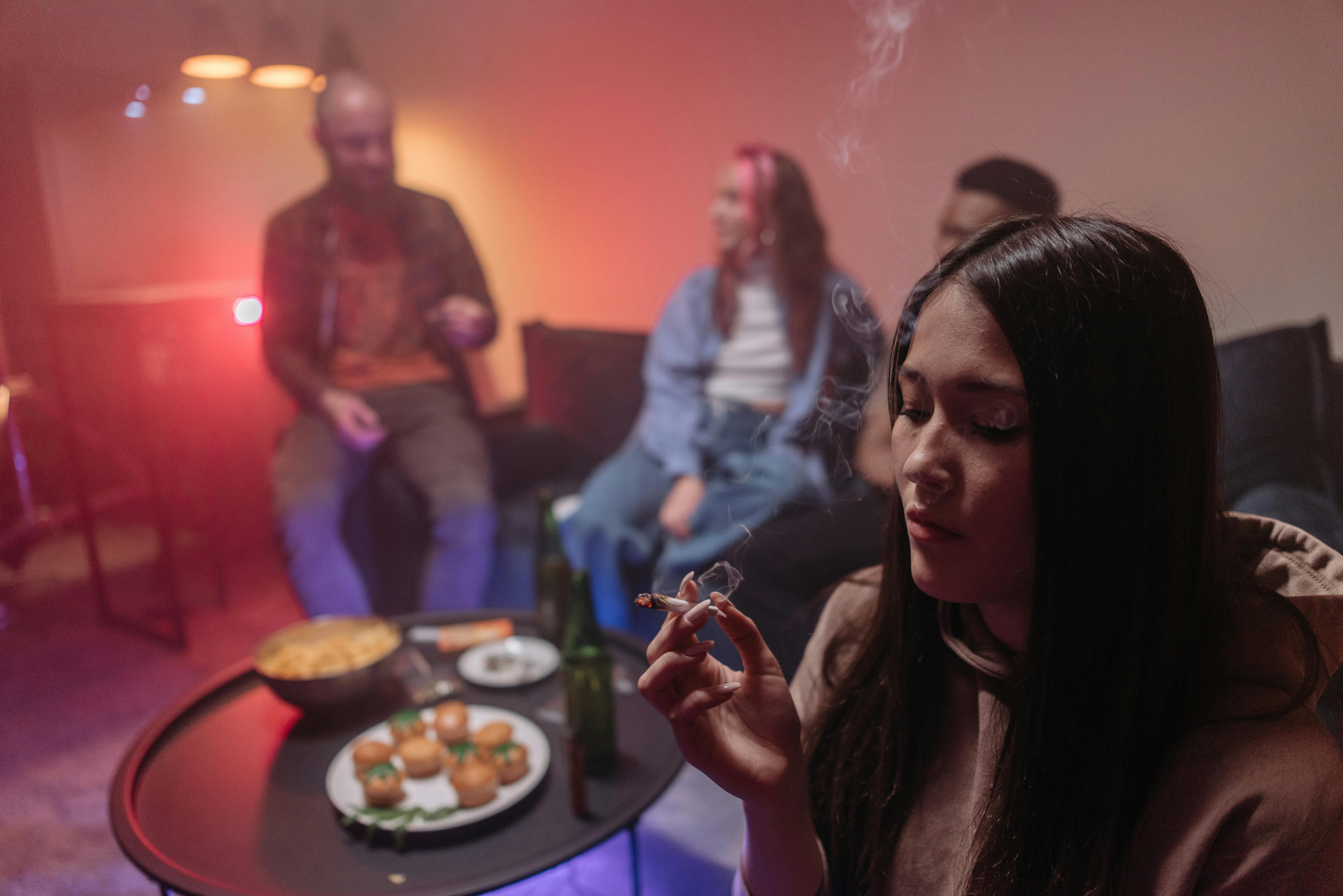 A Woman Smoking Cigarette Near People Sitting on a Couch · Free Stock Photo