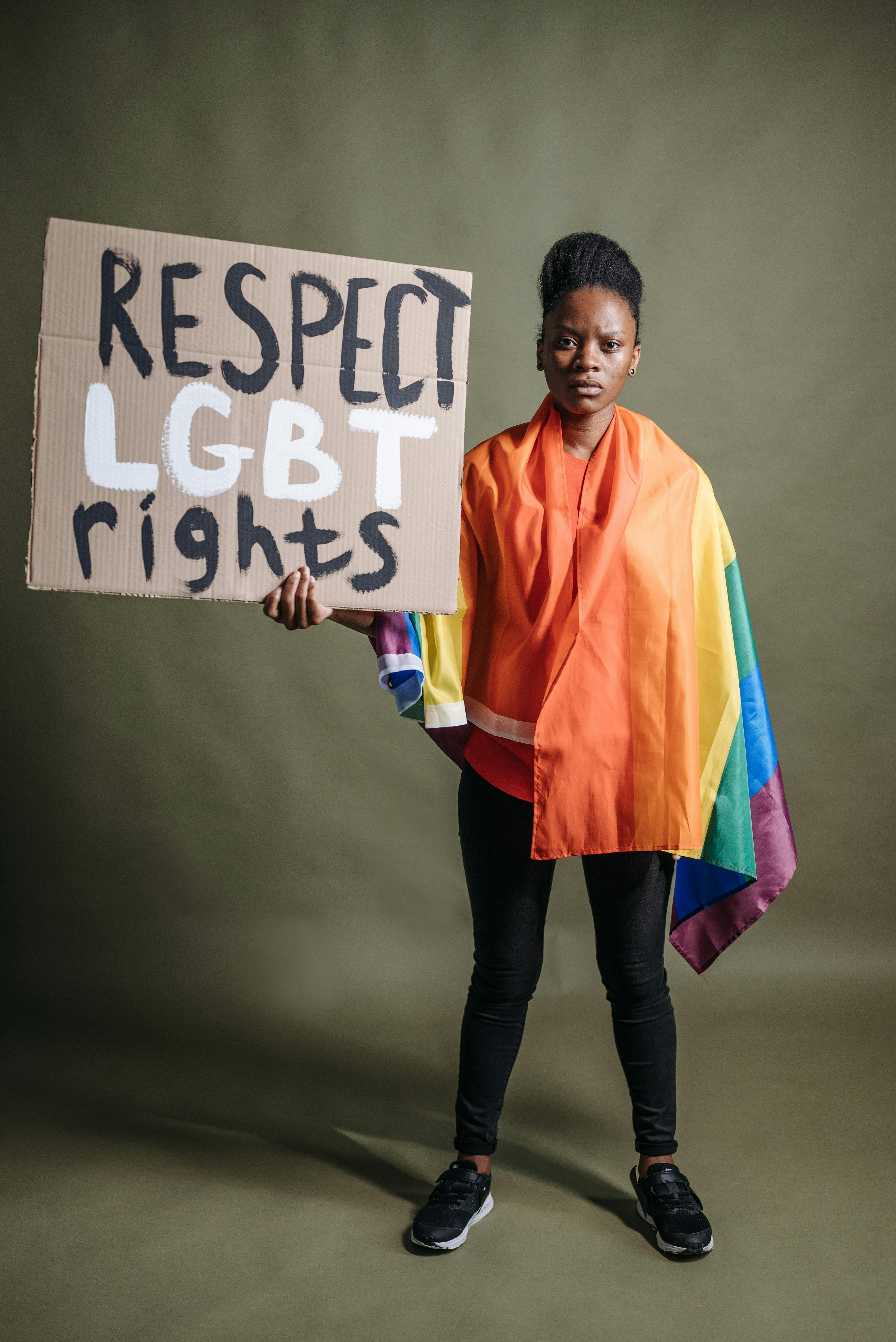 Woman with a Rainbow LGBT Flag Holding a Protest Sign · Free Stock Photo
