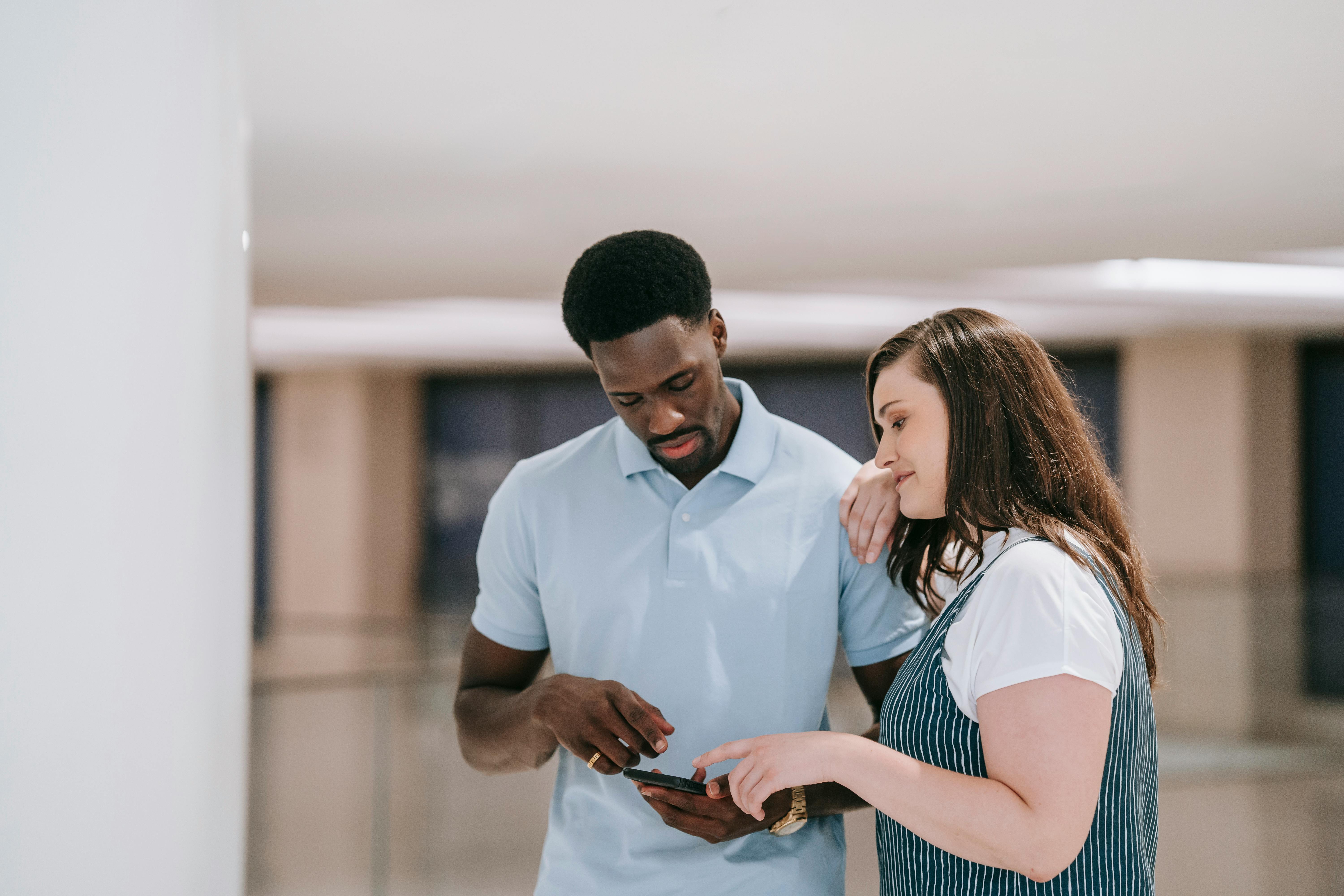 Man and Woman Looking at the Screen of a Mobile Phone · Free Stock Photo