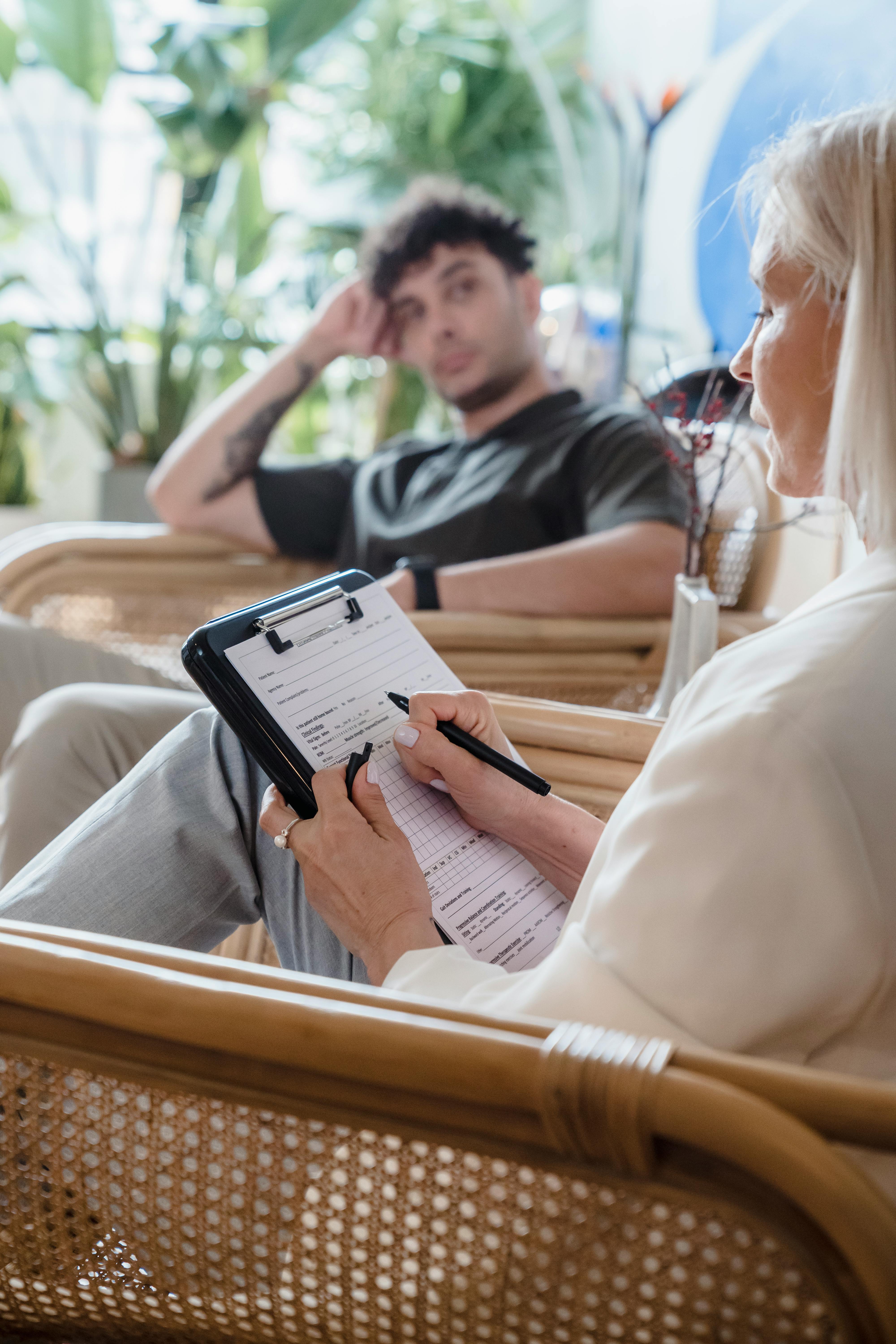 Woman psychologist taking notes on clipboard while talking with client ...