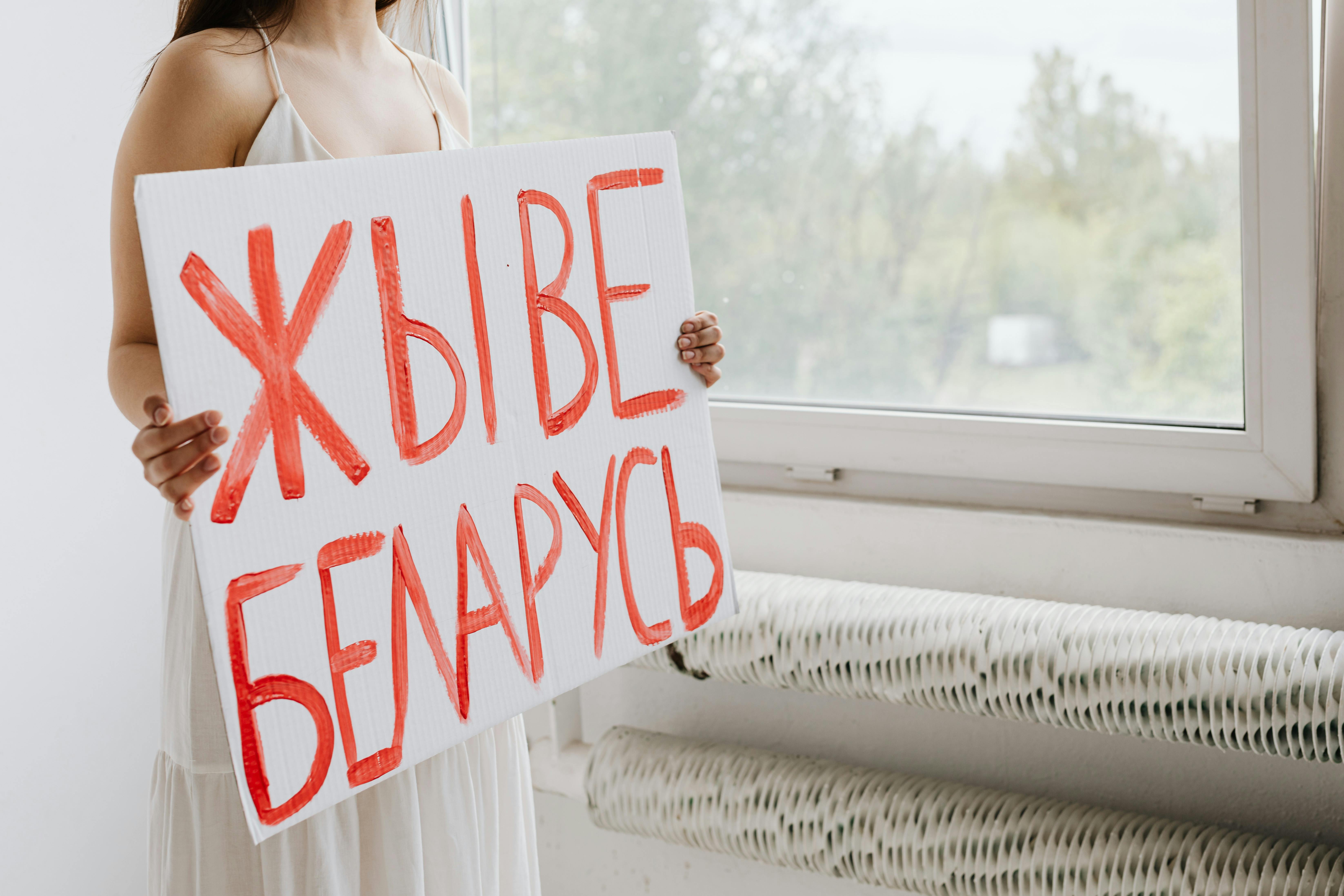 A Person Standing Near the Glass Window while Holding a Placard with ...