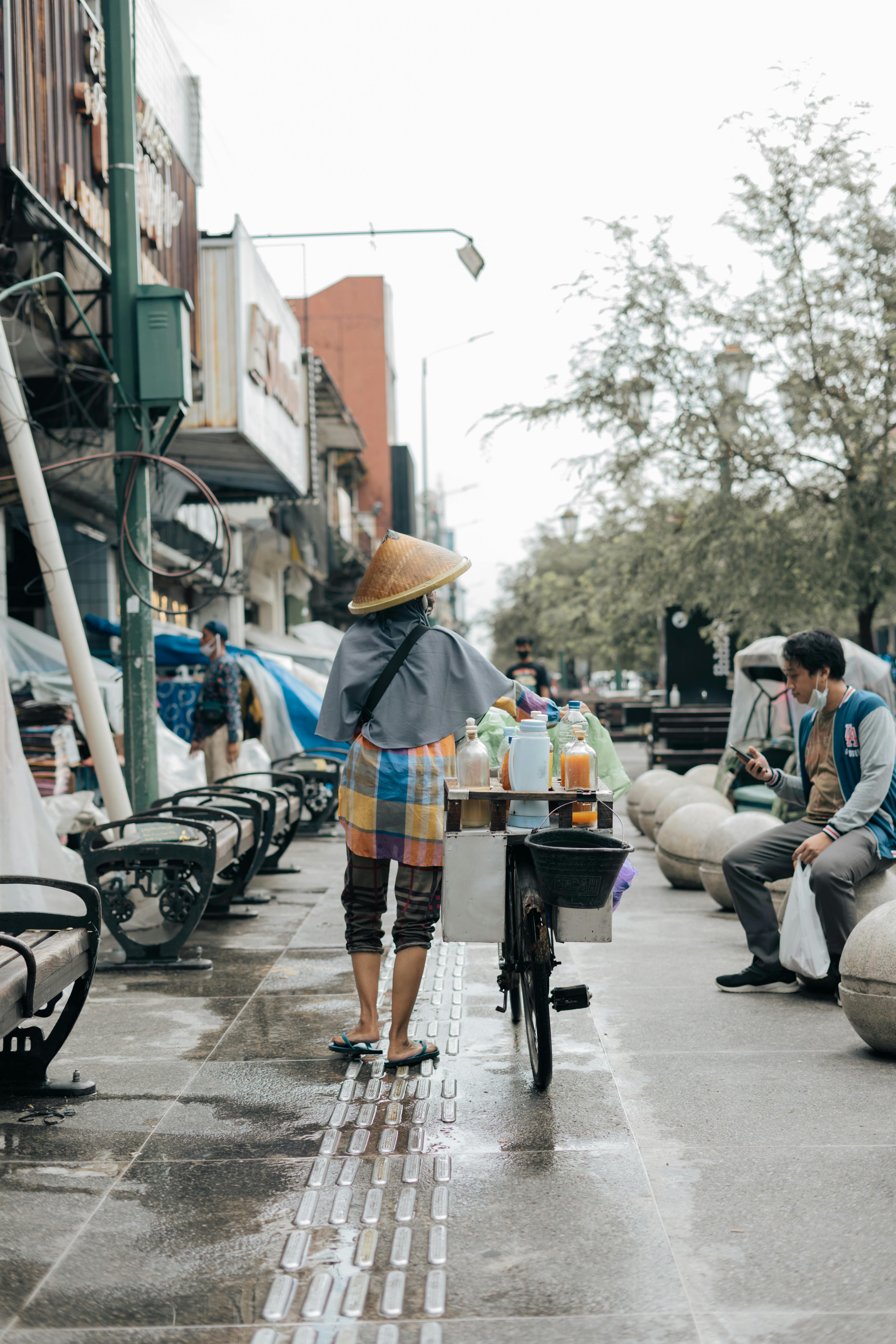 Backview of a Street Vendor walking with his Bicycle on a Side Street ...