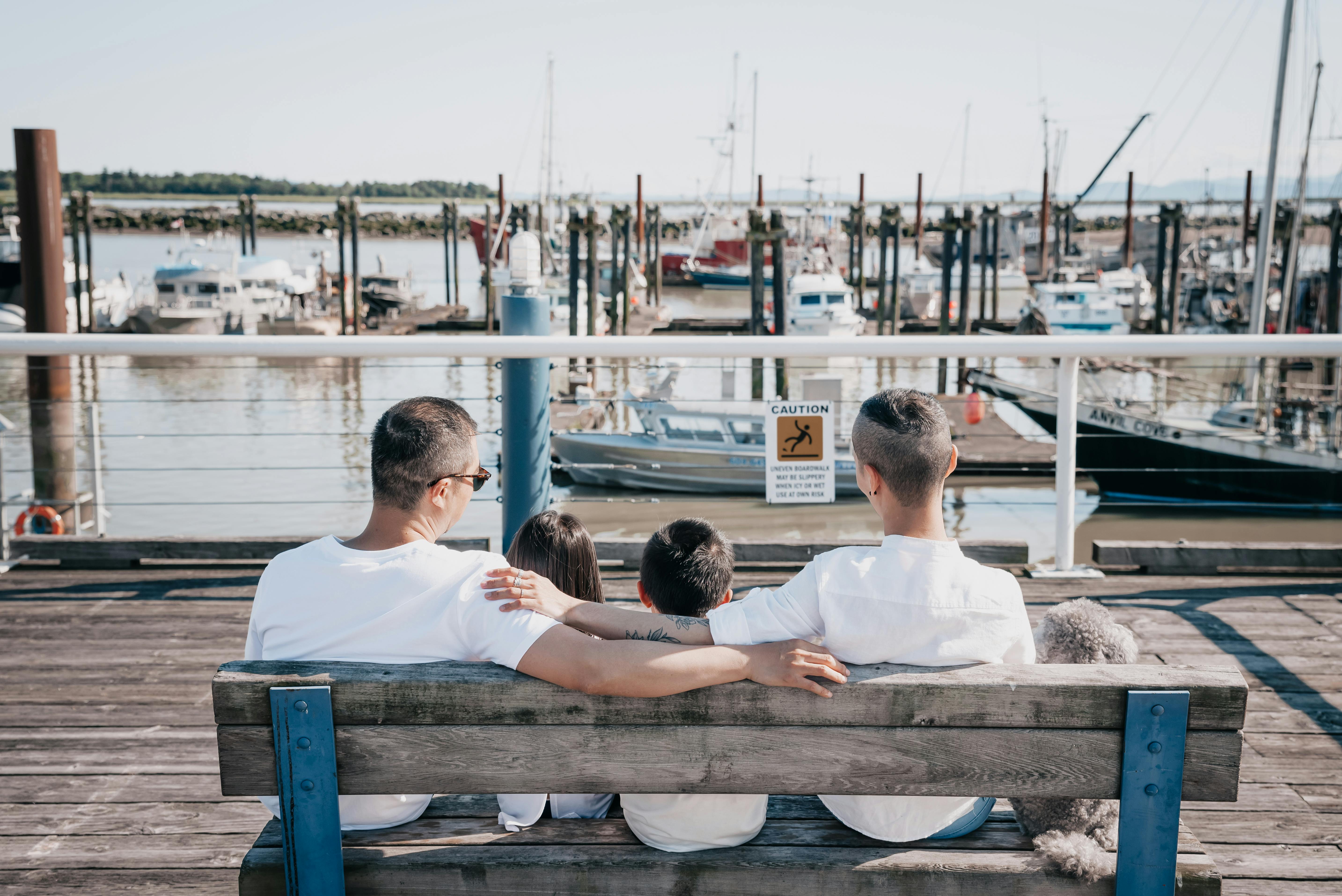 Back View of Family Sitting Close to Each Other on a Wooden Bench ...