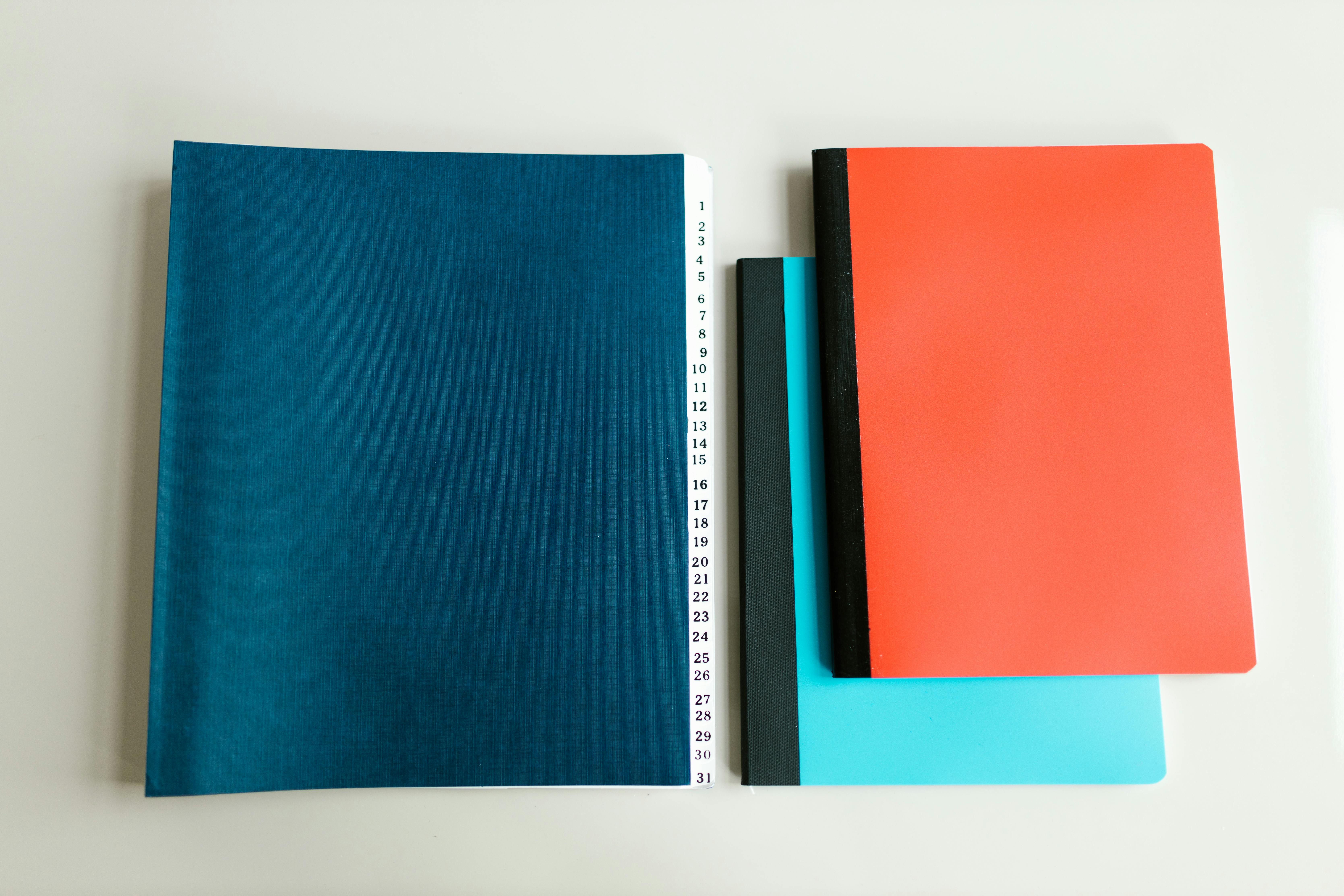 Close-Up Shot of Notebooks on a White Surface · Free Stock Photo