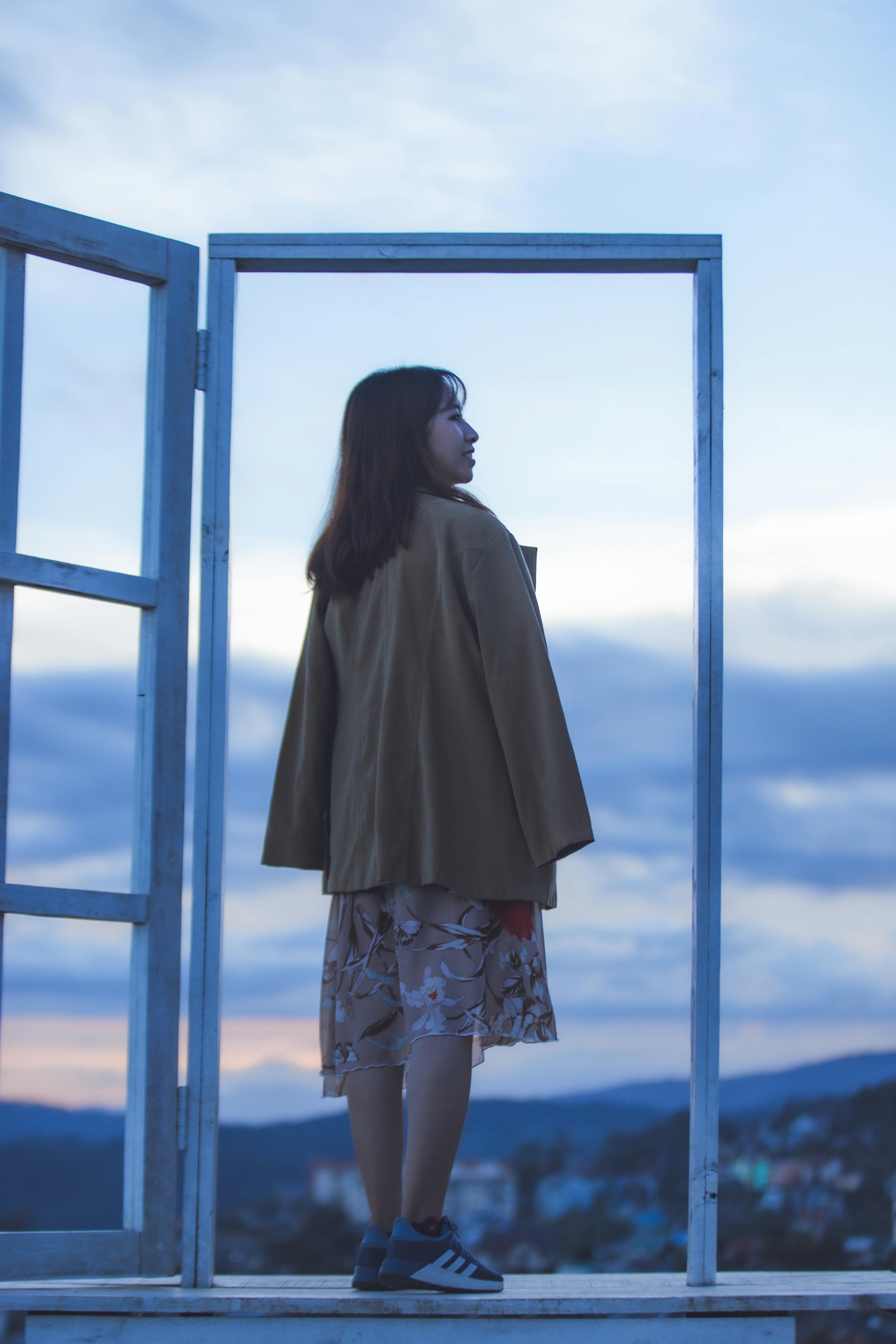 A Woman with Jacket Draped Over Shoulders Standing on a Door Frame ...