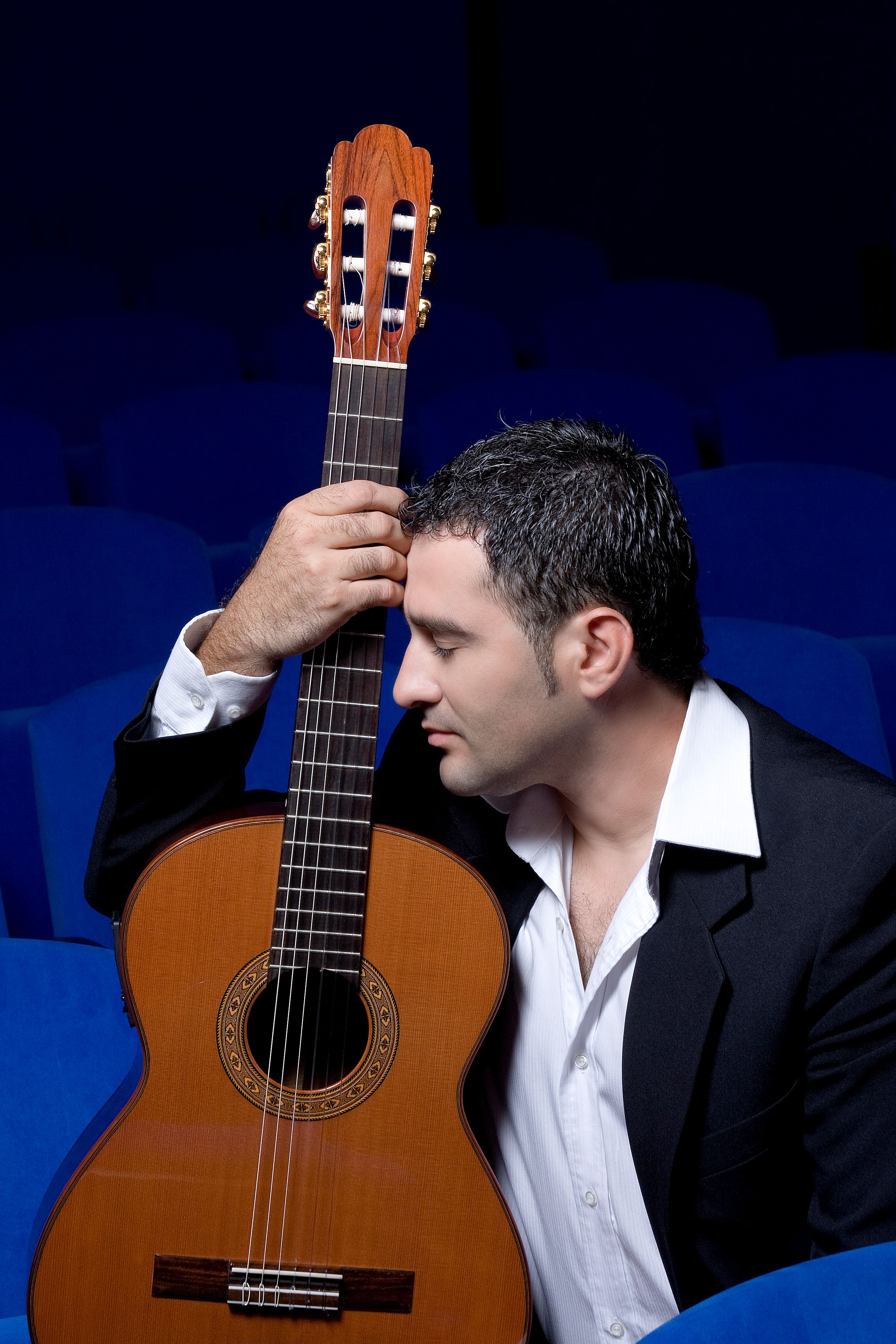 Man in a Black Suit Holding a Brown Acoustic Guitar · Free Stock Photo