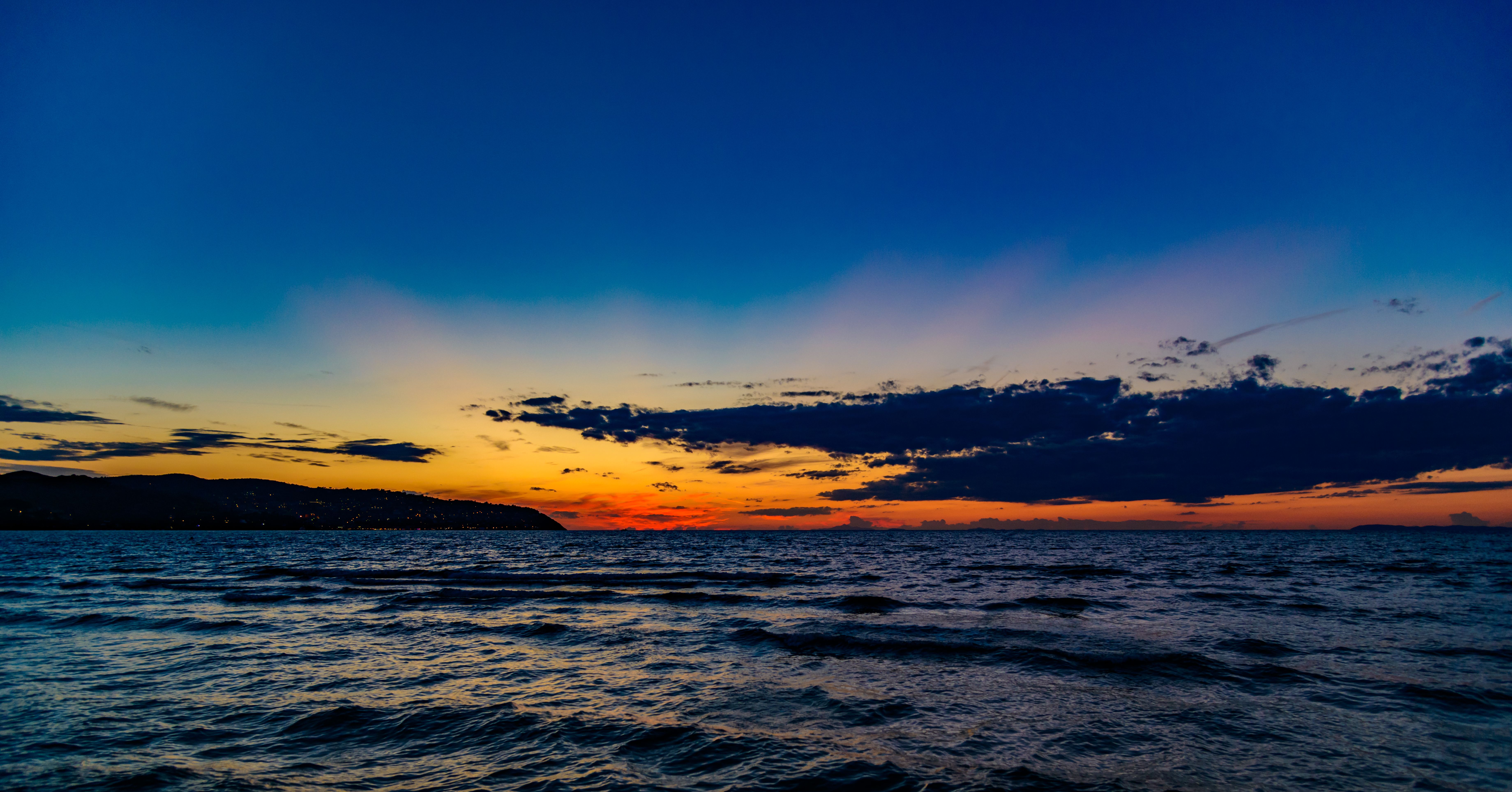 A Scenic View of Ocean Under Sunset Sky · Free Stock Photo