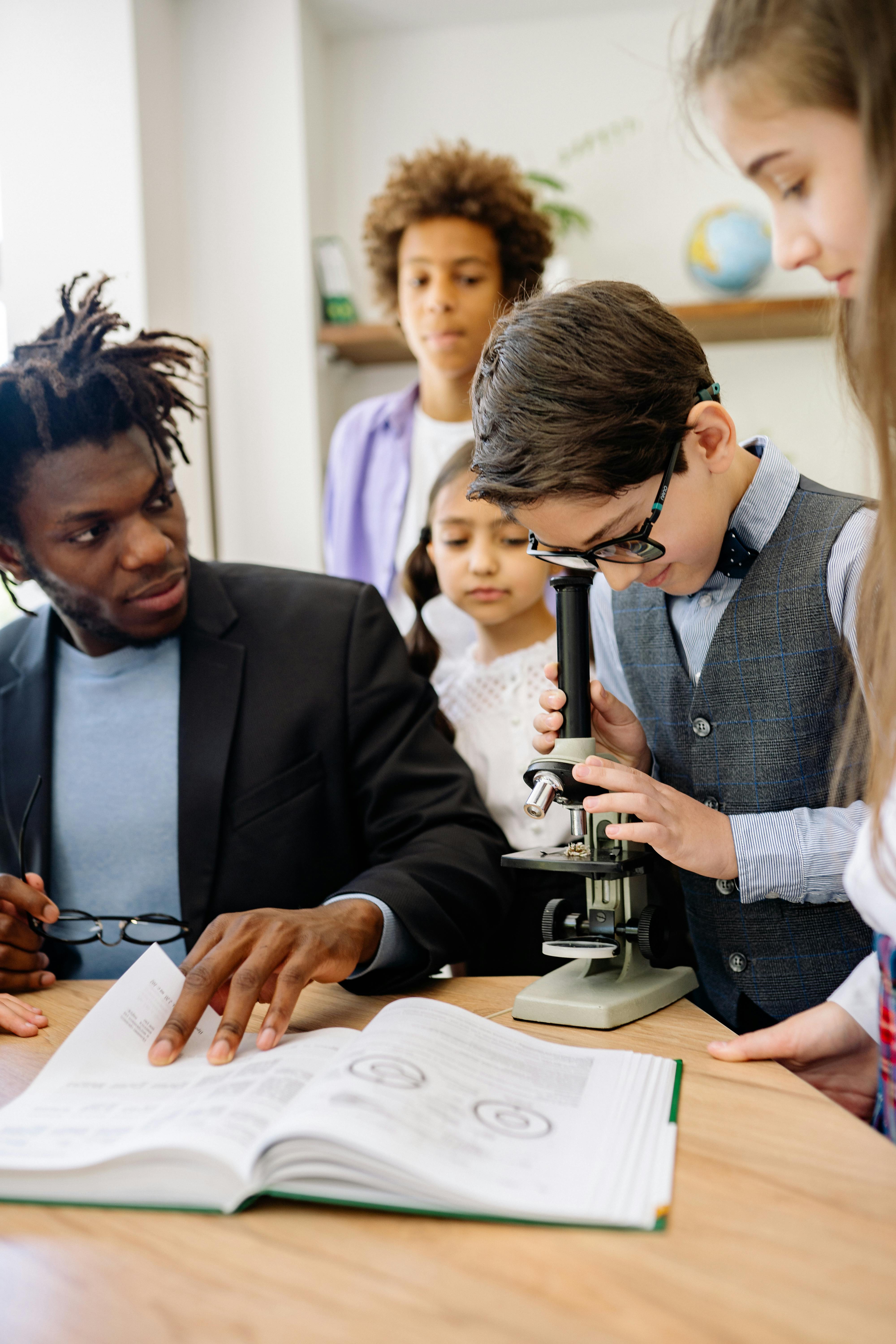 A Boy Using a Microscope beside His Teacher · Free Stock Photo