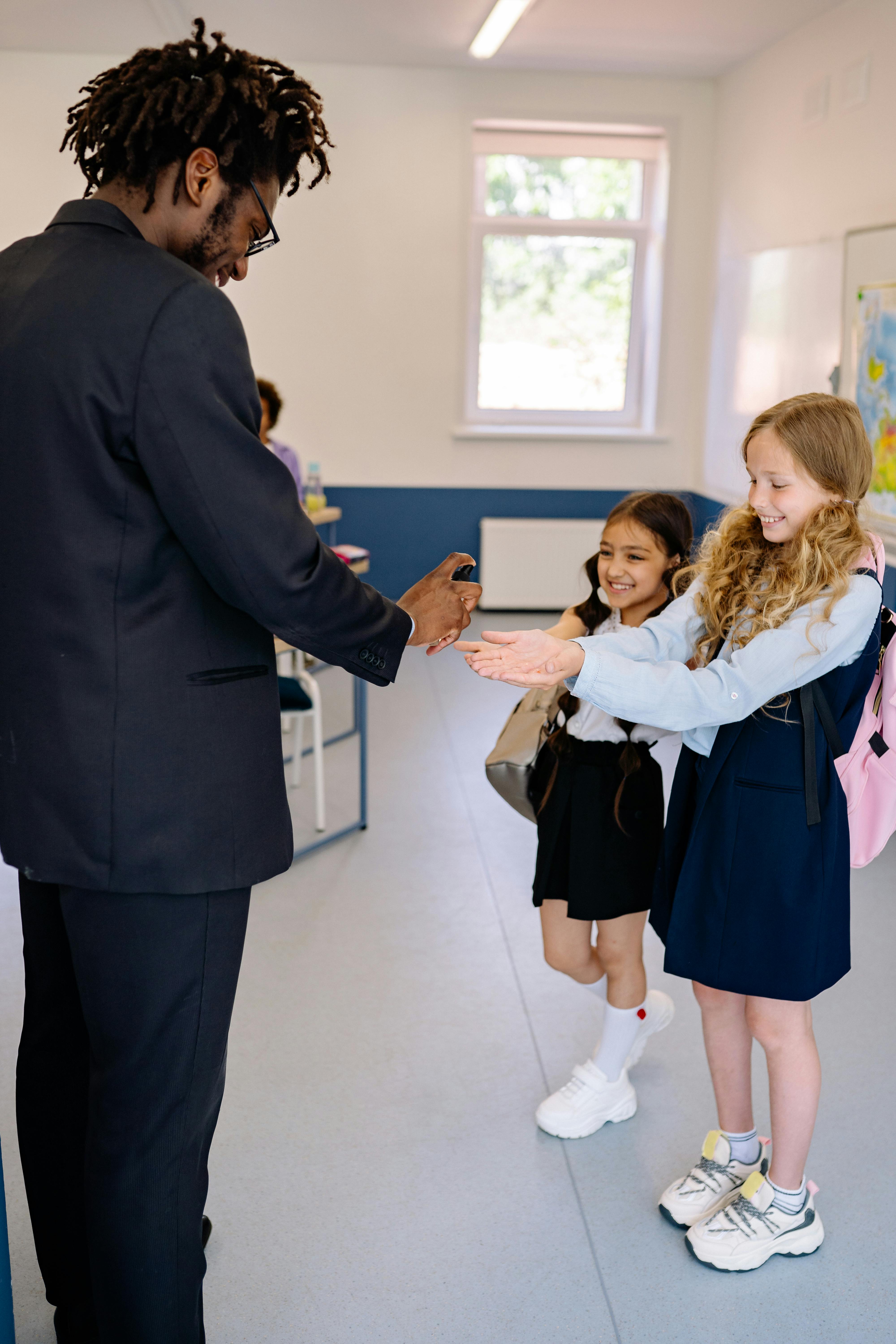 A Teacher Sanitizing the Hands of His Students · Free Stock Photo