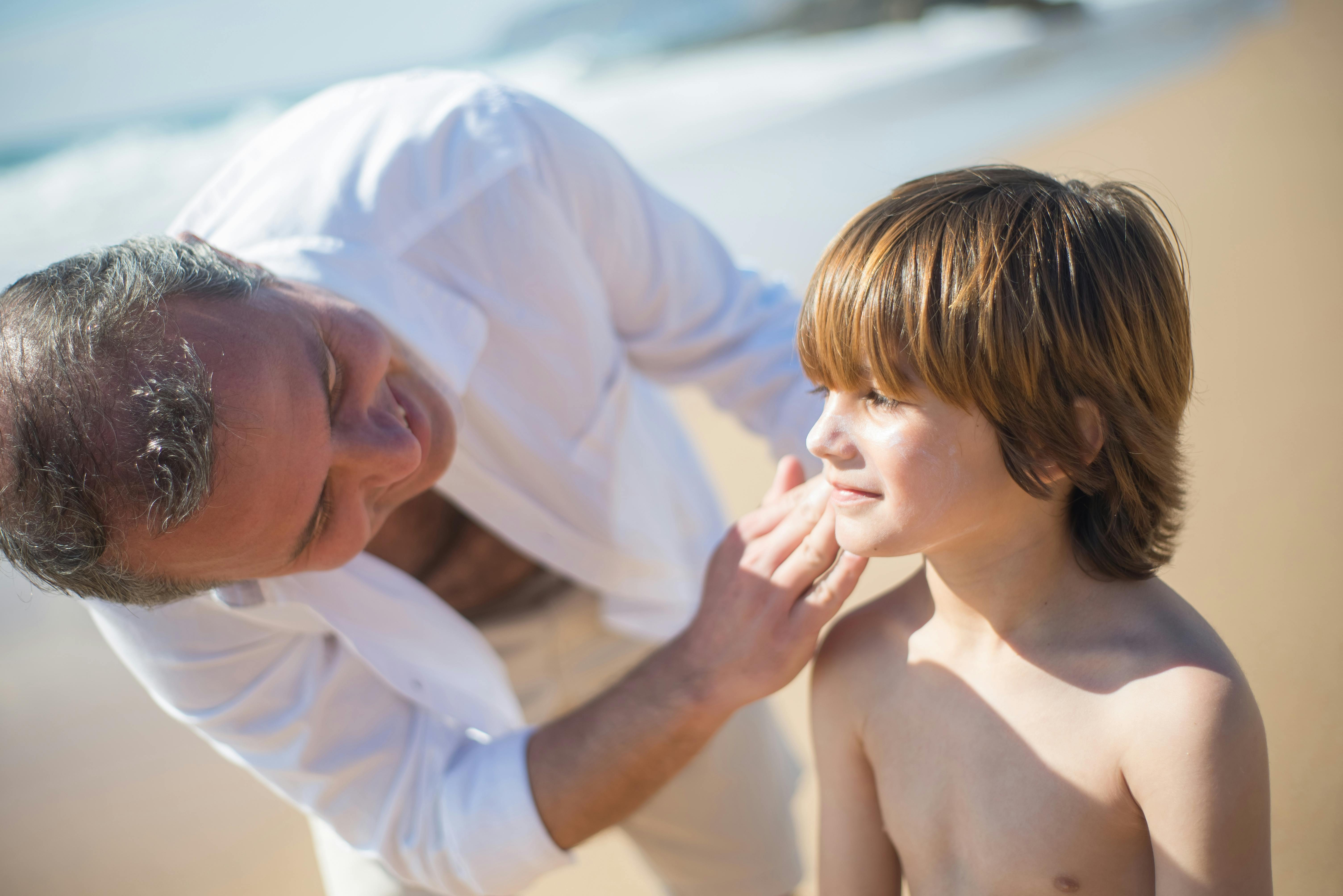 A Man Applying a Sunscreen on His Son's Face · Free Stock Photo