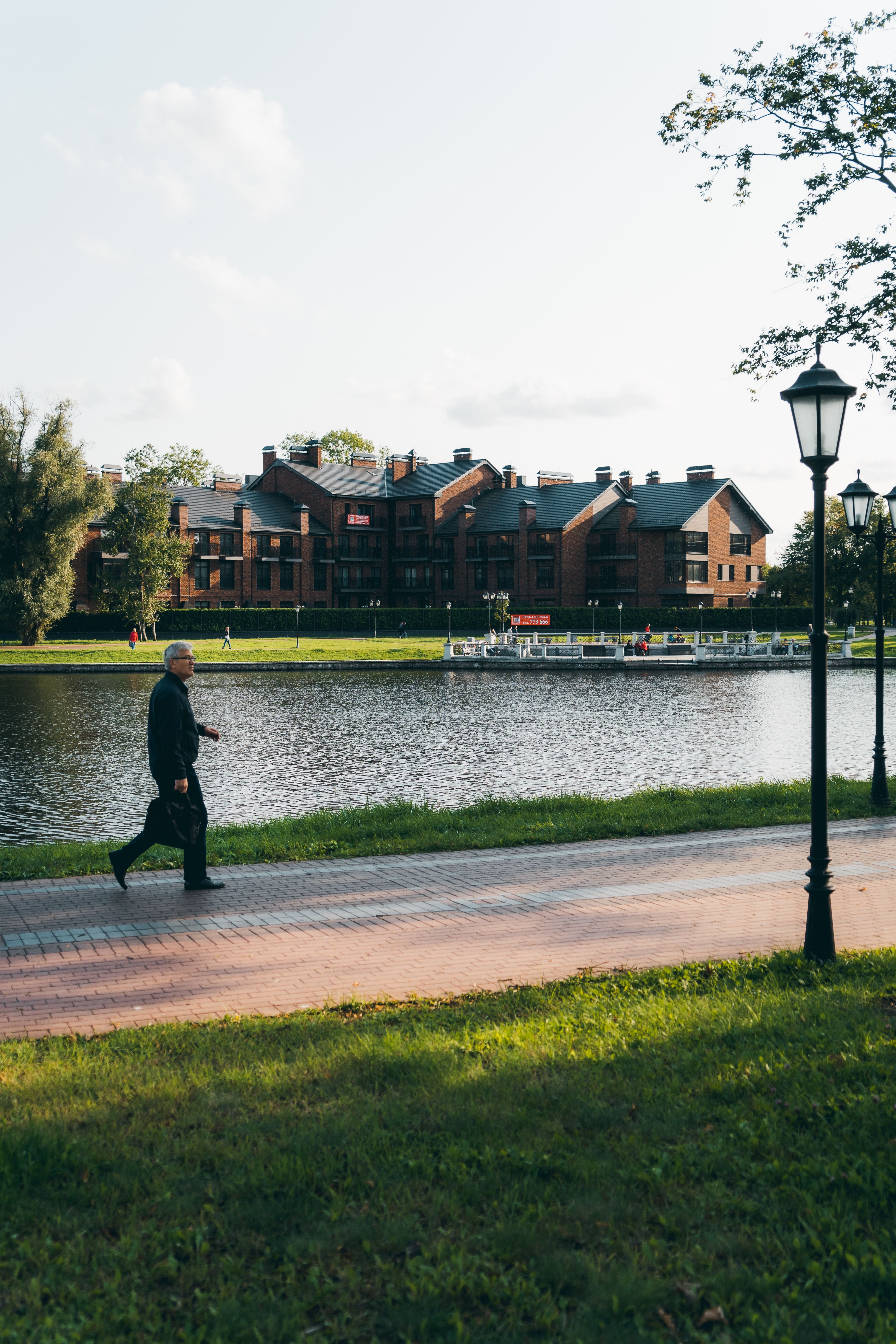 Person Walking on Sidewalk Near the River · Free Stock Photo