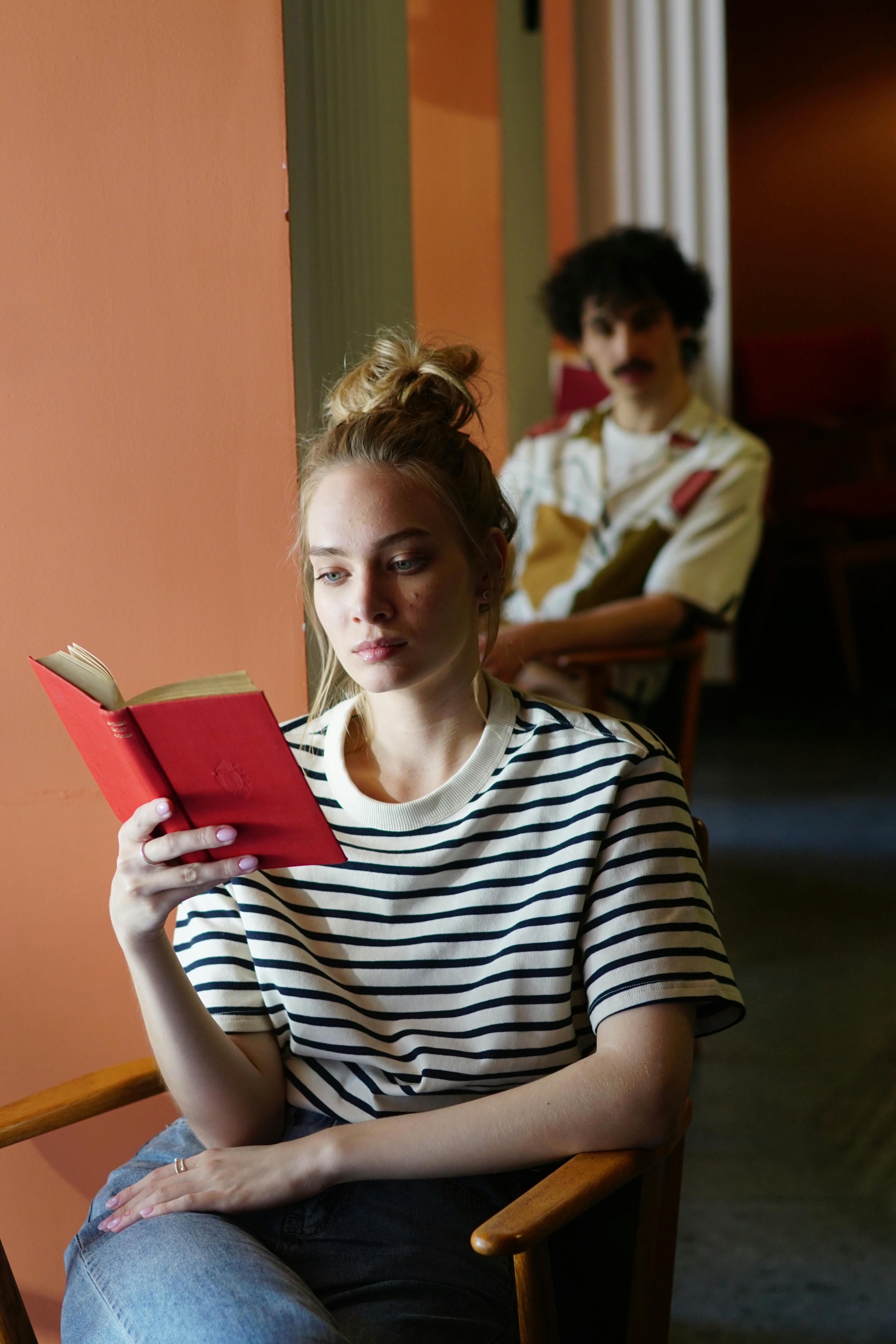 A Woman Sitting While Reading a Book · Free Stock Photo