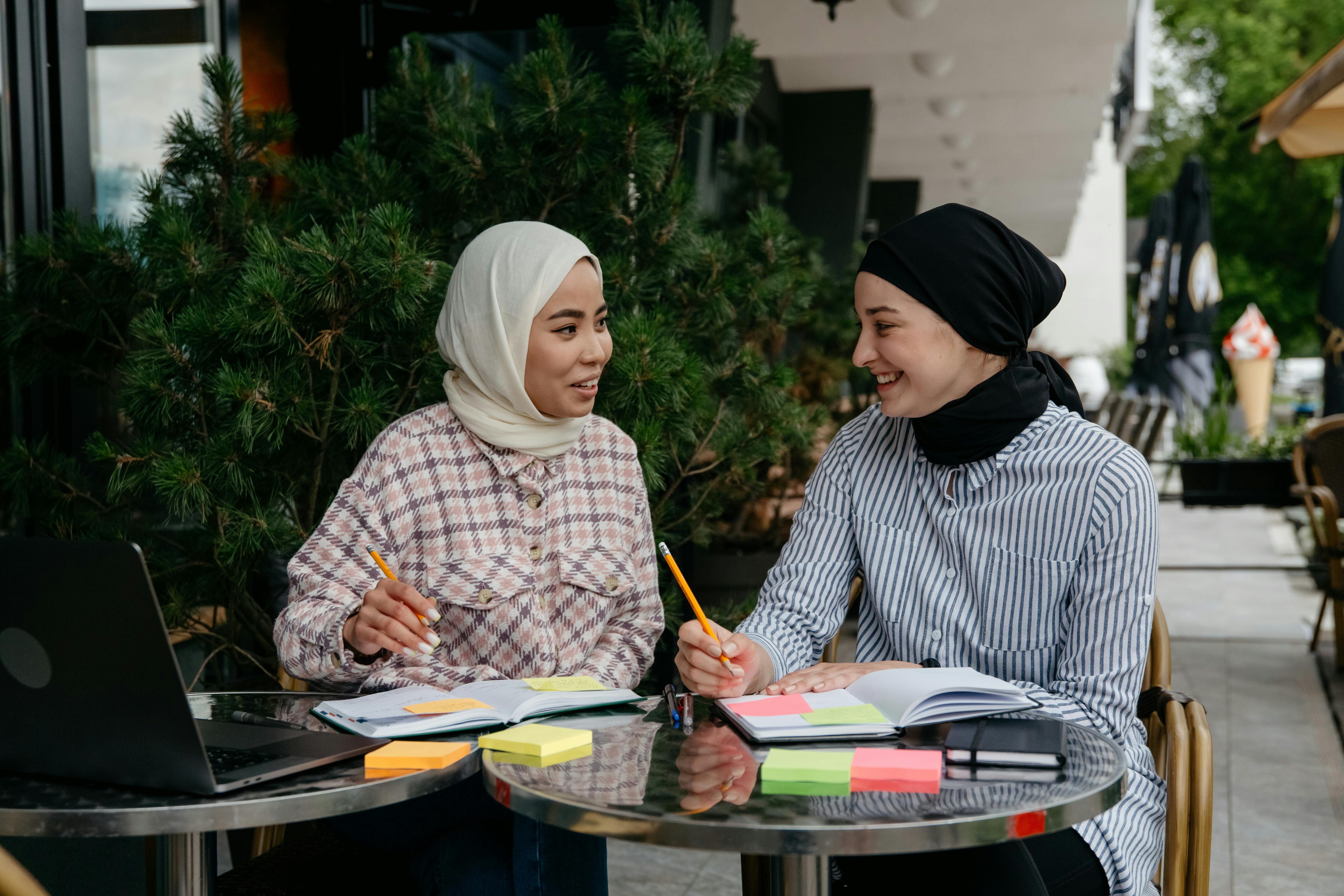 Two Women Sitting Outside a Cafe Using Laptop · Free Stock Photo Two Women Sitting Outside a Cafe Using Laptop · Free Stock Photo