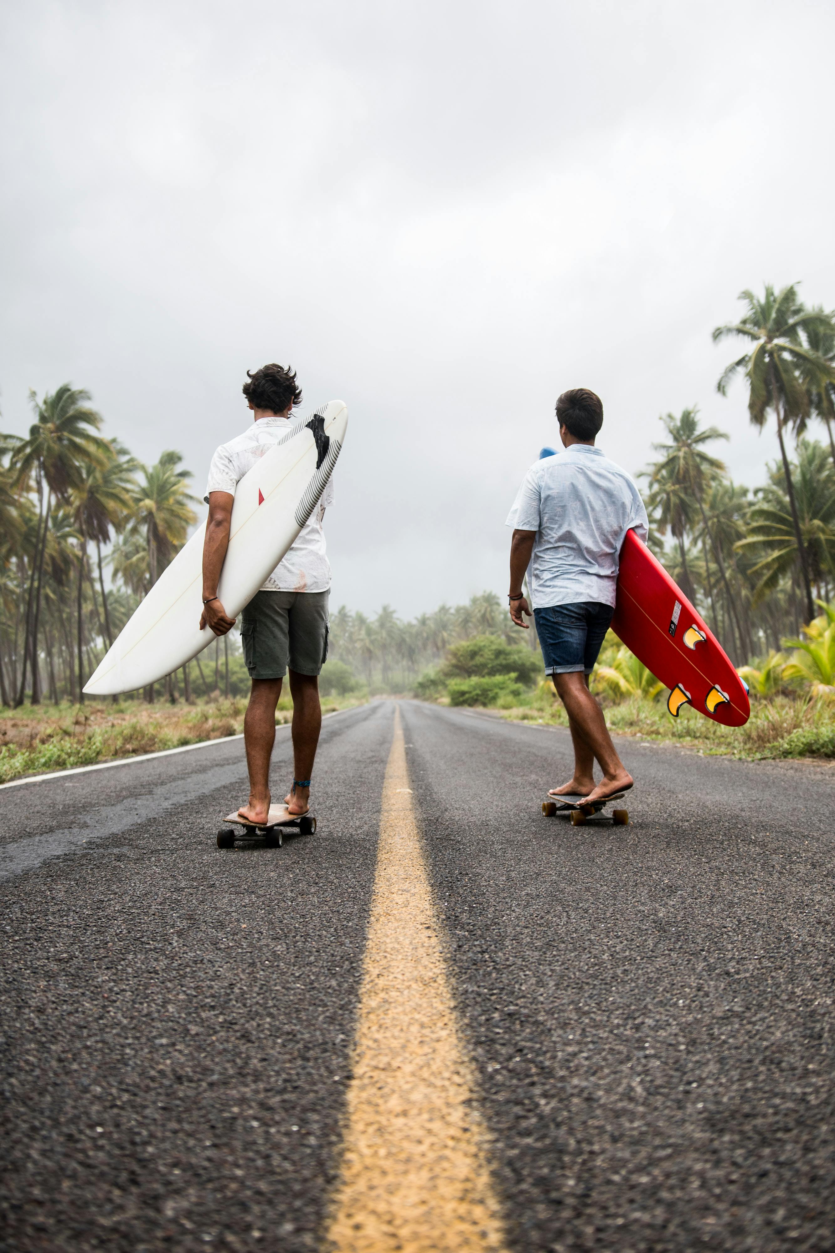 Men Riding Long Boards while Carrying Surf Boards · Free Stock Photo