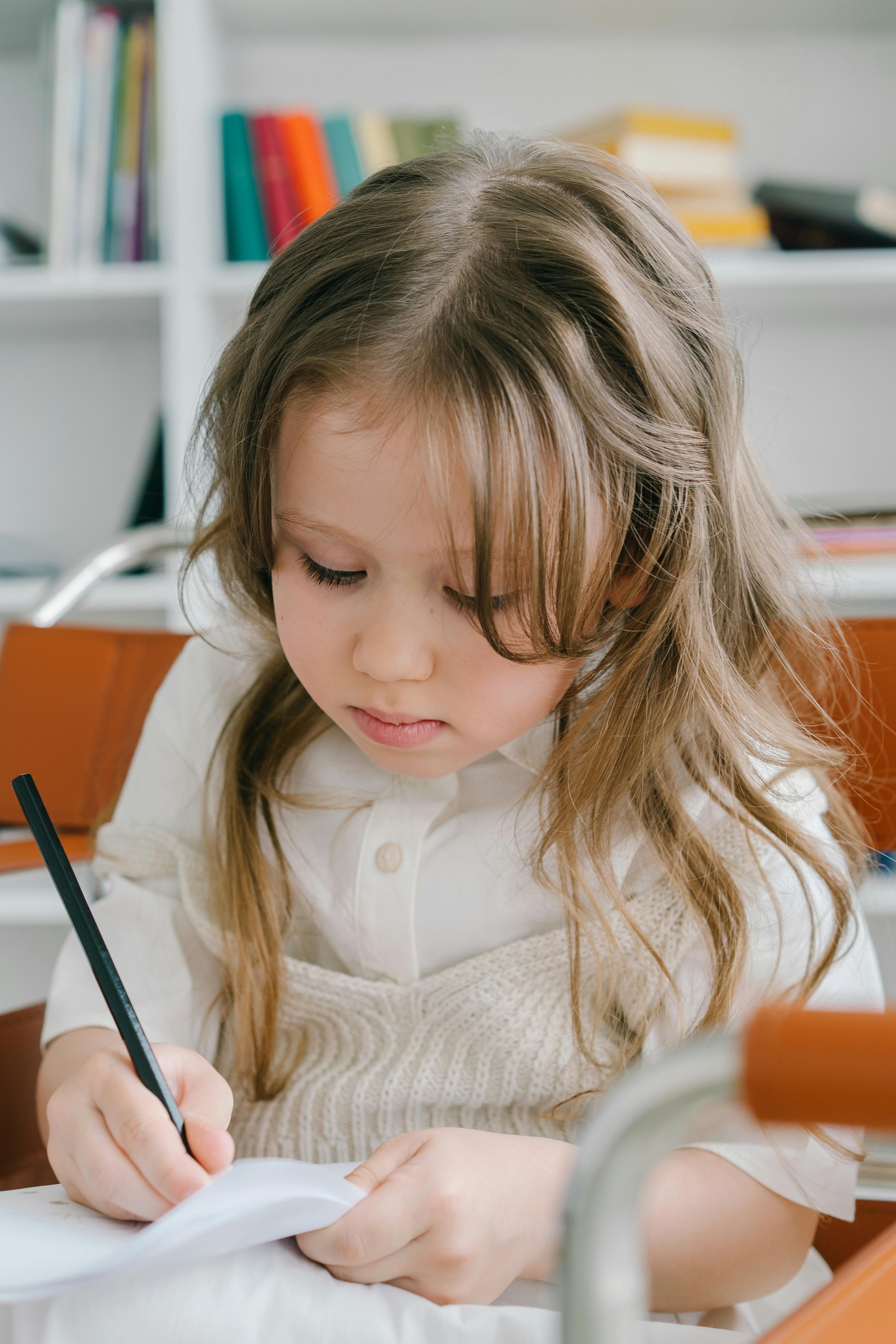 Photo of a Girl Using a Black Pencil to Write on Paper · Free Stock Photo