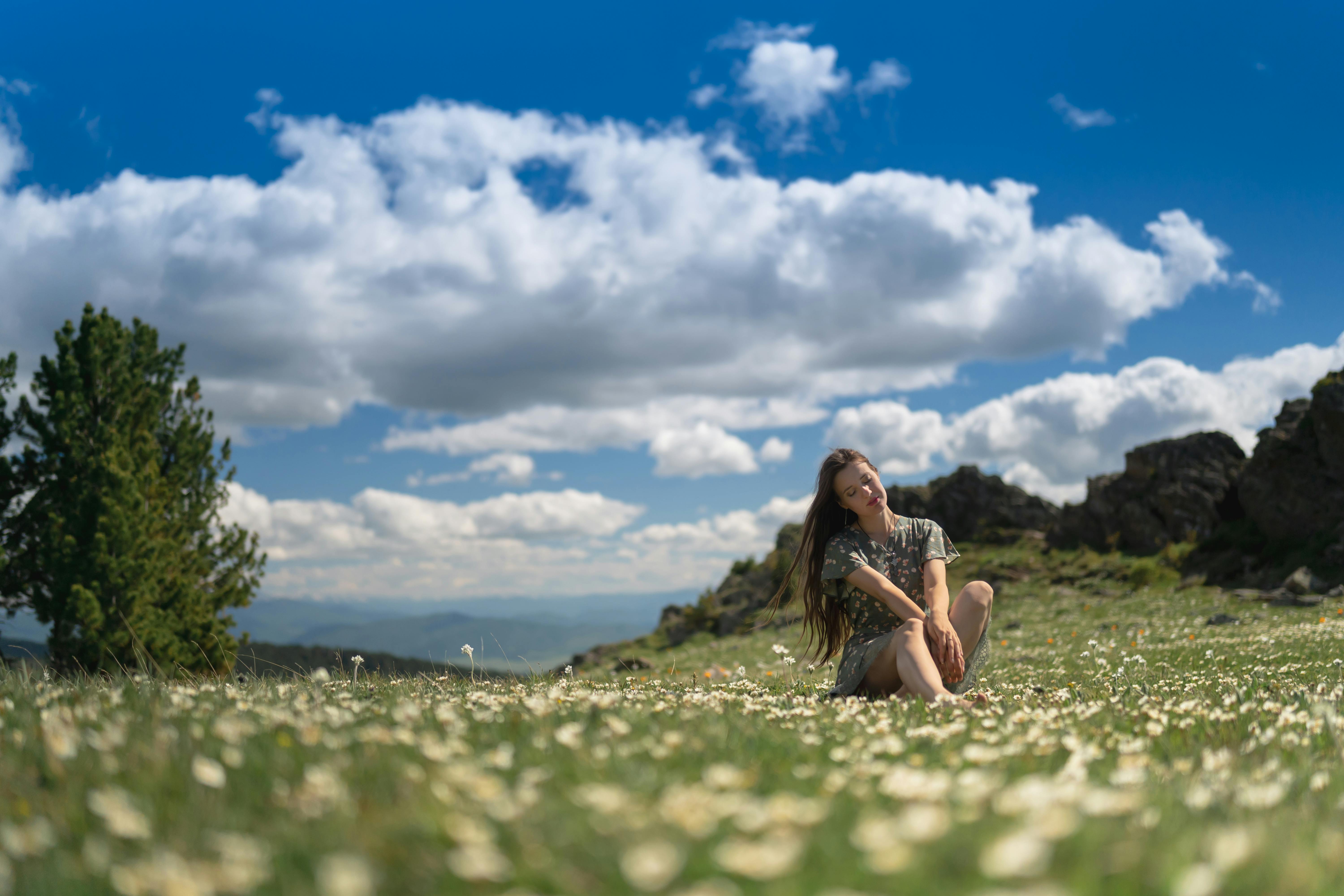 Photograph of a Woman Sitting on the Ground with Flowers and Grass ...