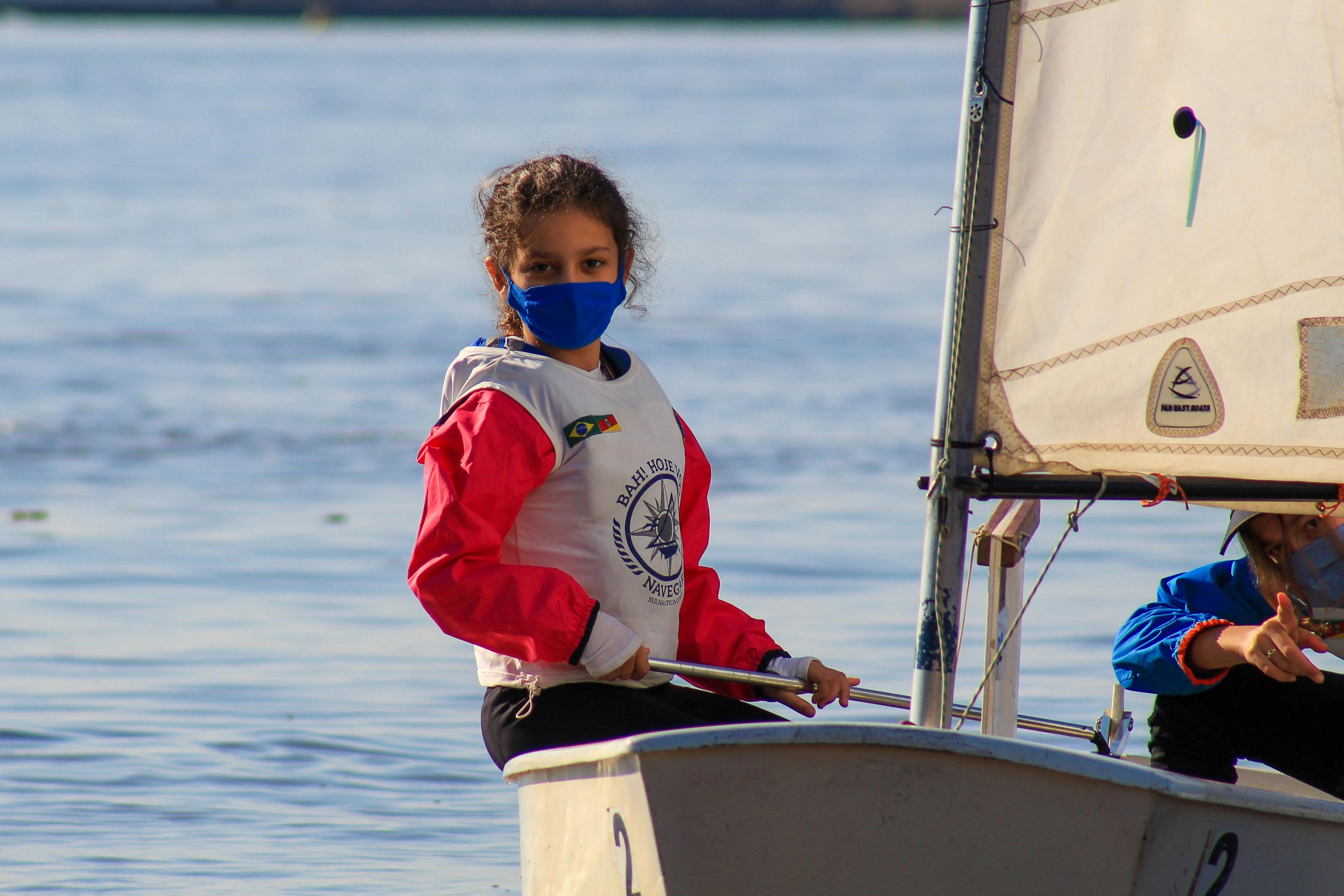 A Girl Wearing Face Mask Sitting on a White Boat while Seriously ...