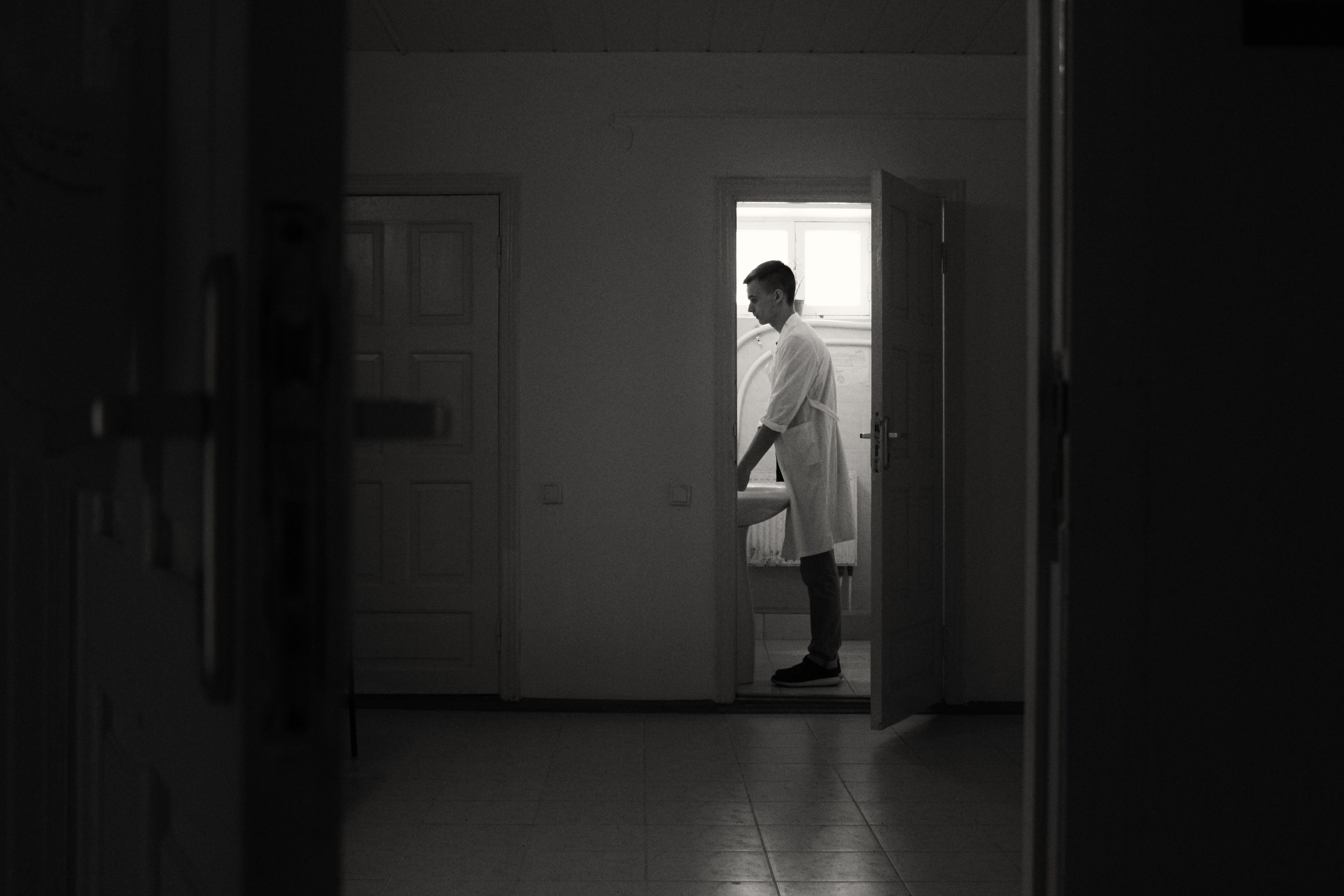A Grayscale of a Man Walking Out the Building · Free Stock Photo