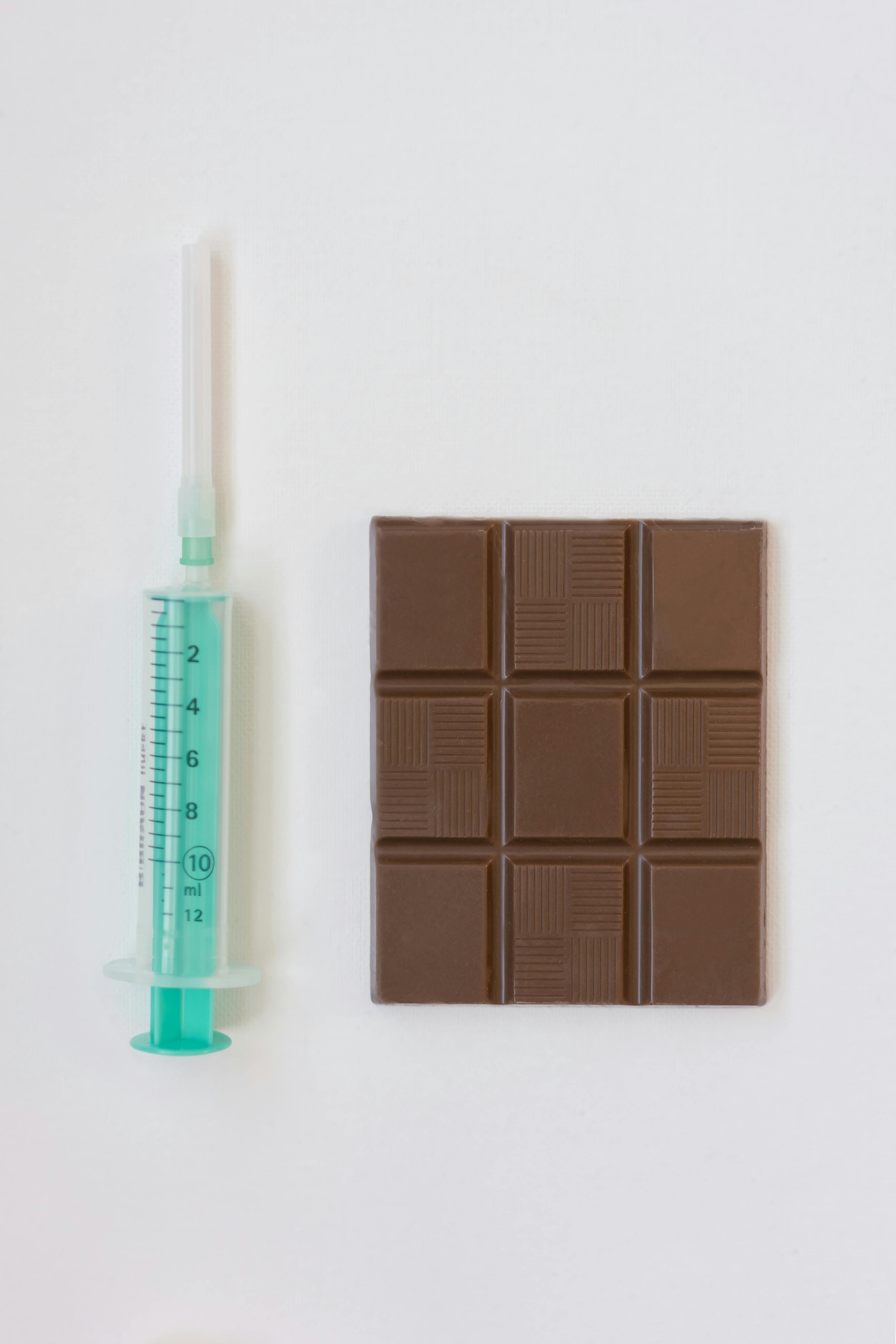 Bar of Chocolate and Syringe on White Table · Free Stock Photo