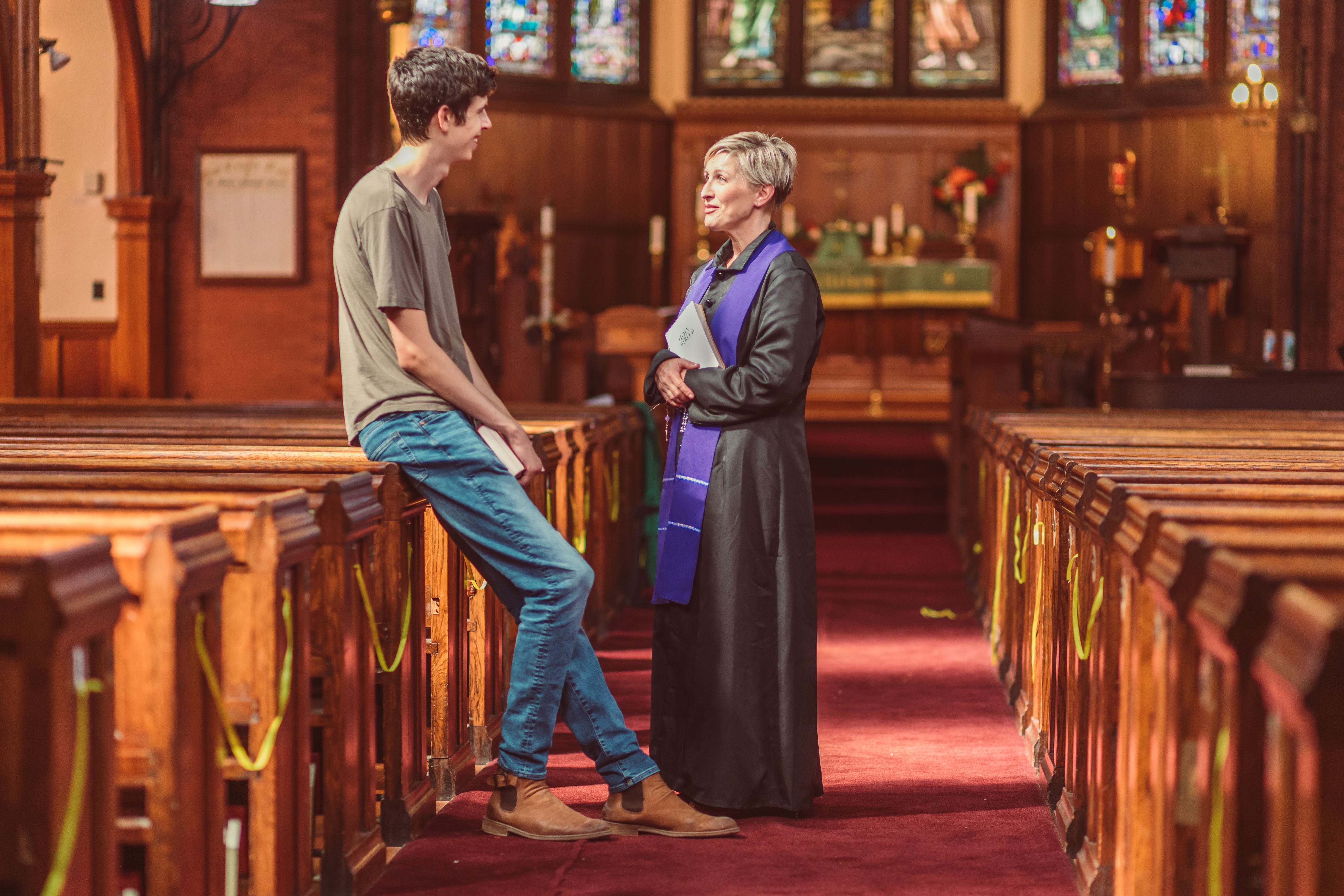 Female Priest Talking to Man Sitting in Church Pew · Free Stock Photo