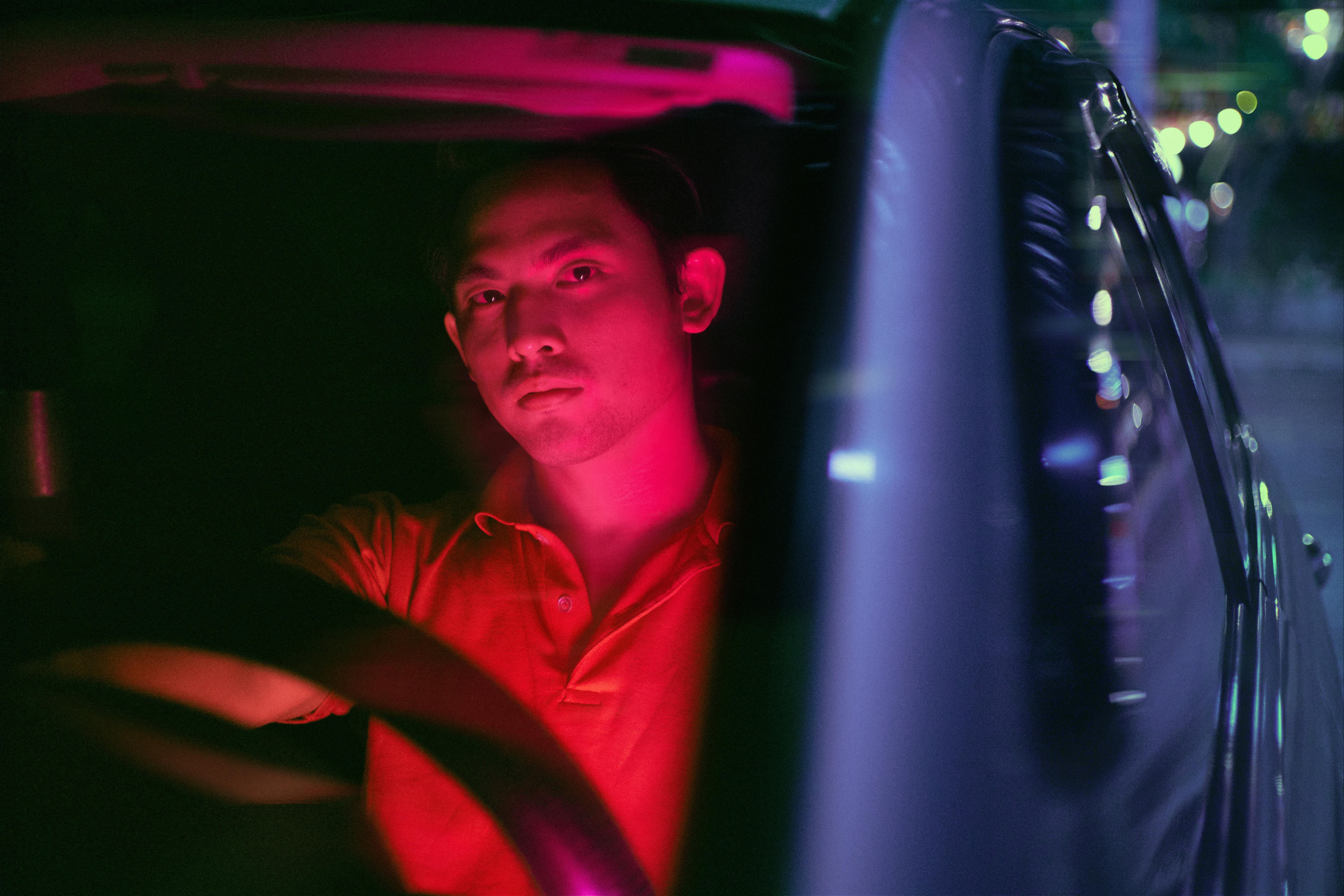 Photo of a Man Inside a Car Illuminated by Red Lights · Free Stock Photo