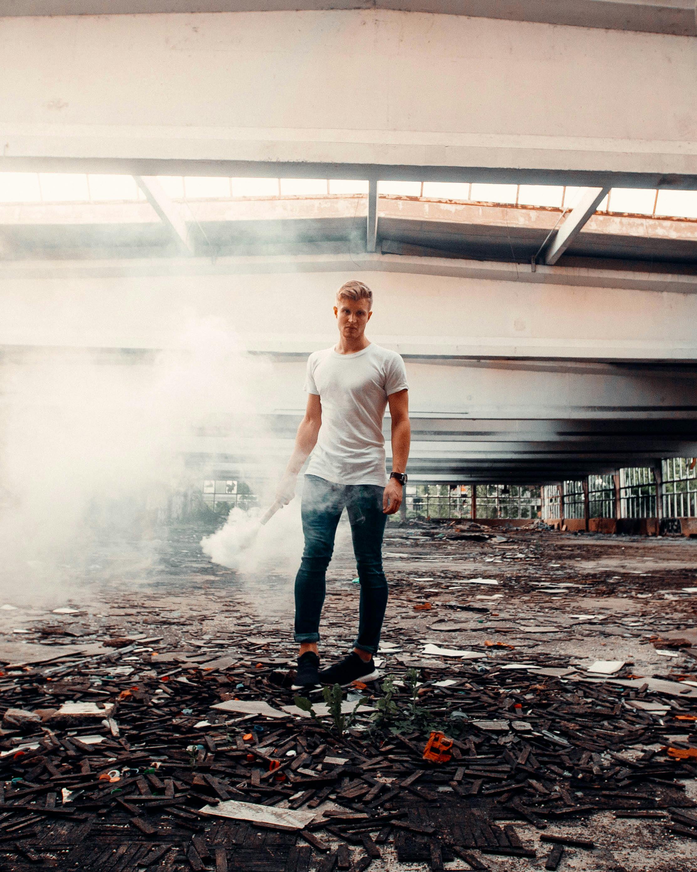 A Man Holding a Flare while Standing on Rubble · Free Stock Photo