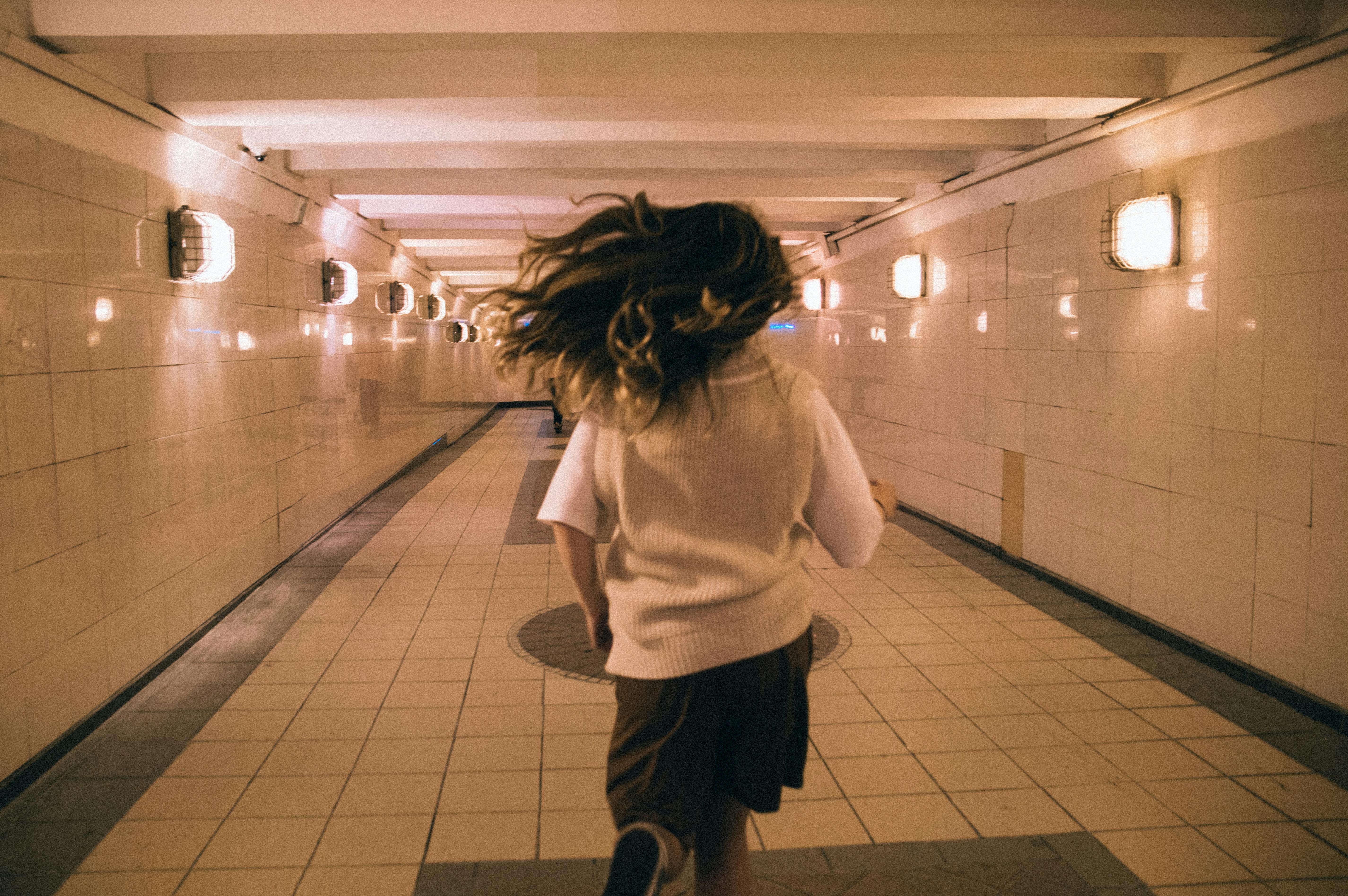 A Woman Running on Tiled Hallway · Free Stock Photo