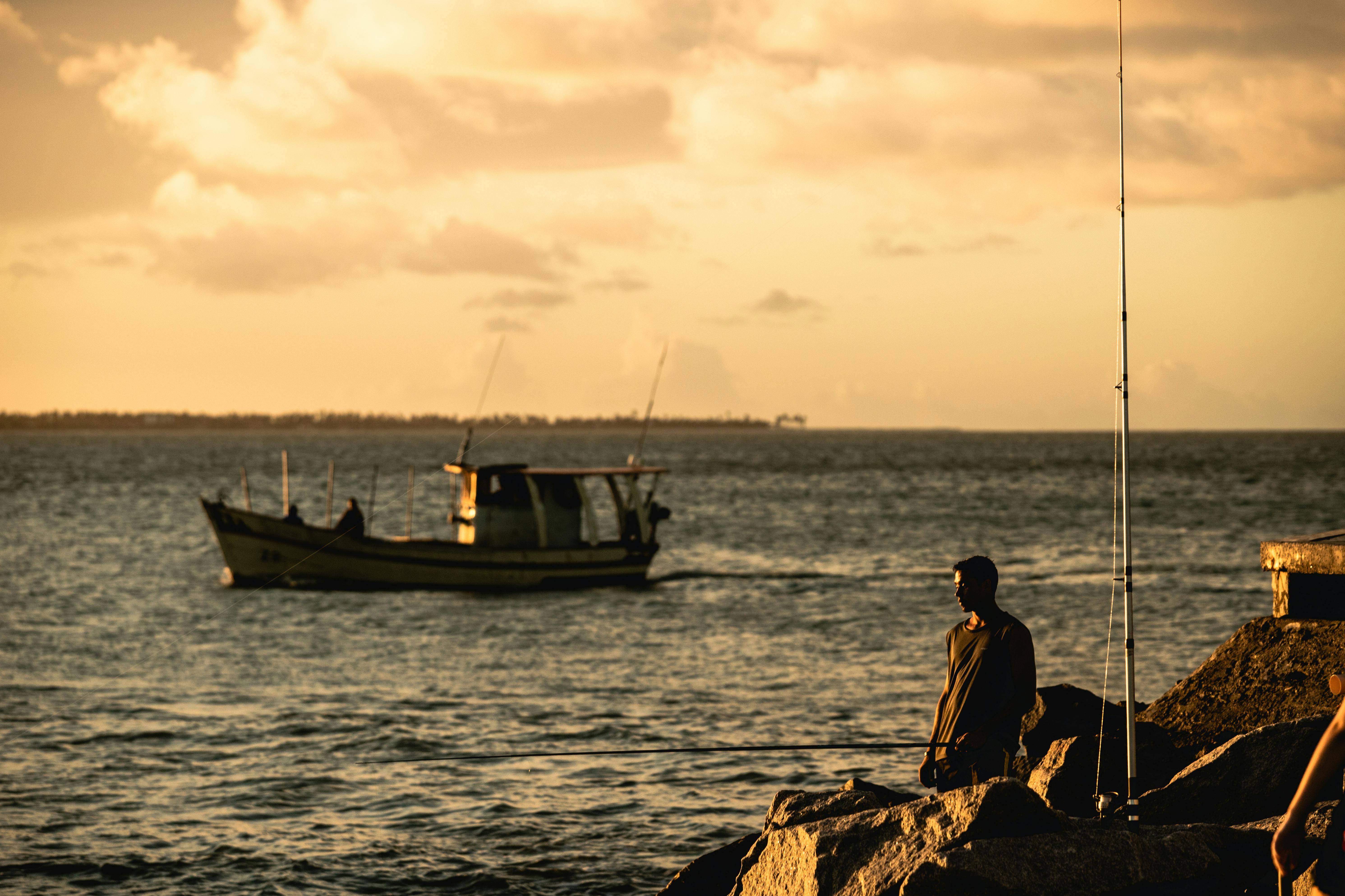 A Mam Fishing on the Rocky Shore · Free Stock Photo