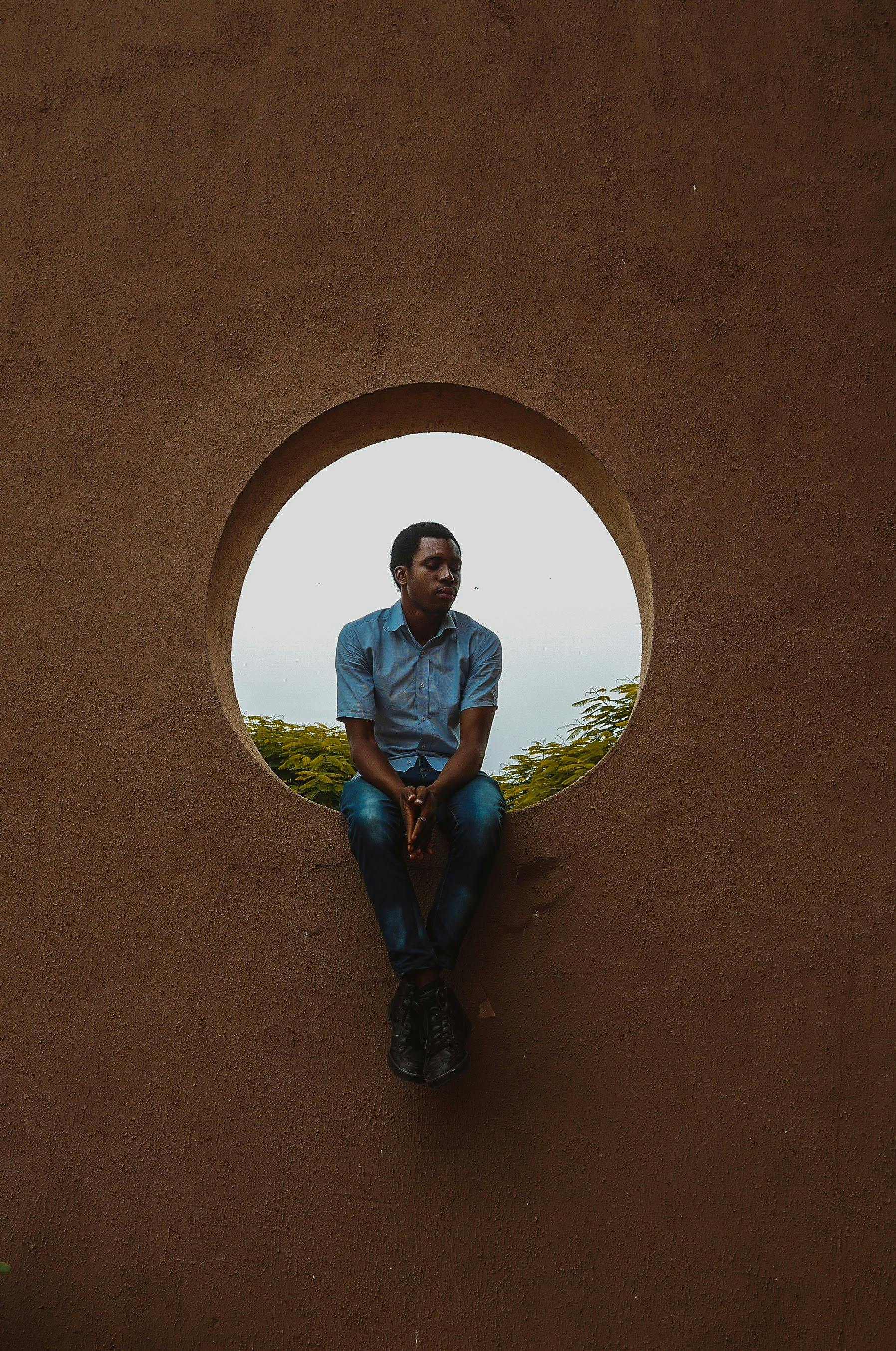 A Man Sitting on a Round Window · Free Stock Photo