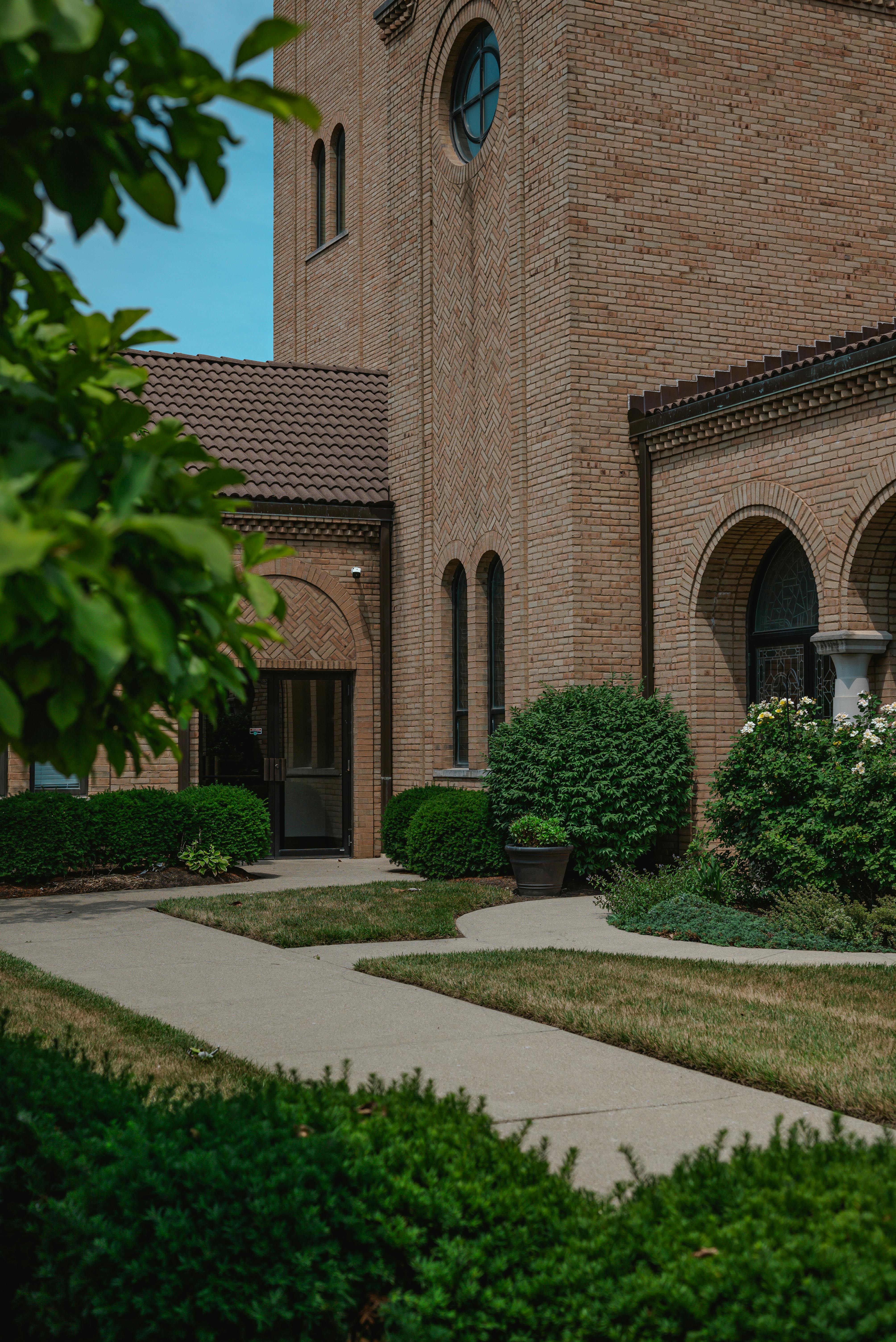 Brown Brick Building With Green Trees and Plants · Free Stock Photo