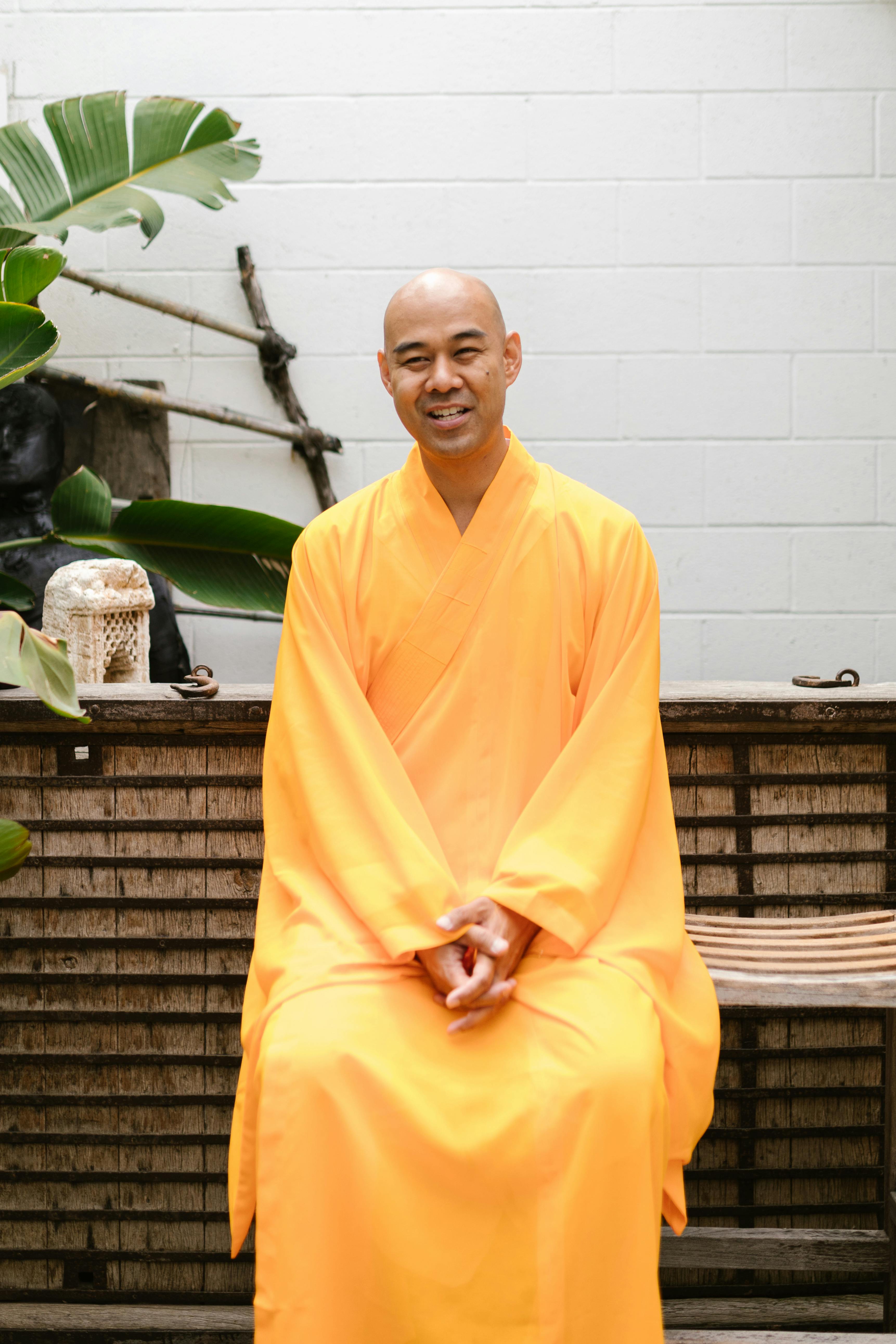 Man in Yellow Robe Sitting on Brown Wooden Bench · Free Stock Photo