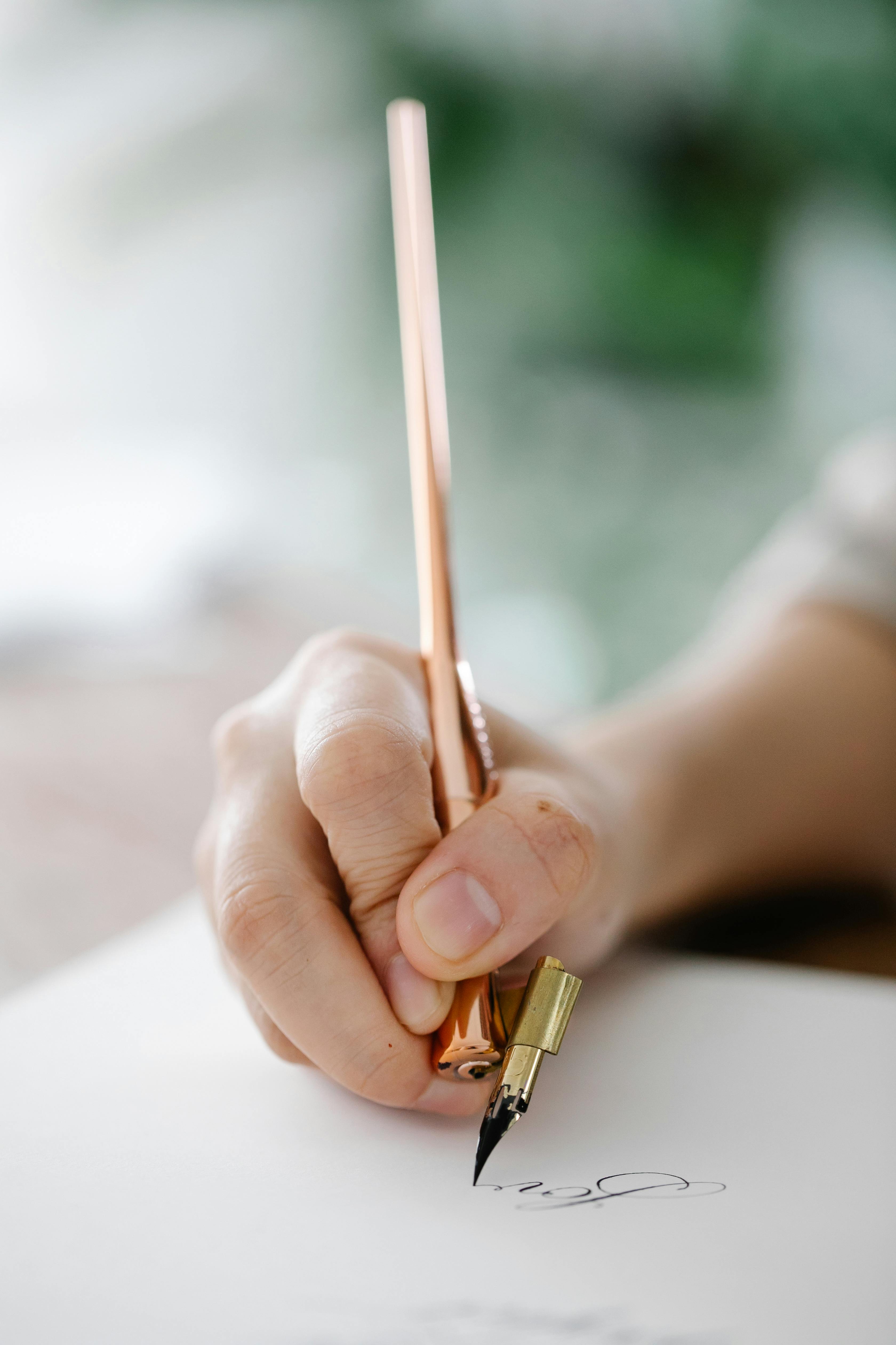 Person Holding Copper Ink Pen · Free Stock Photo