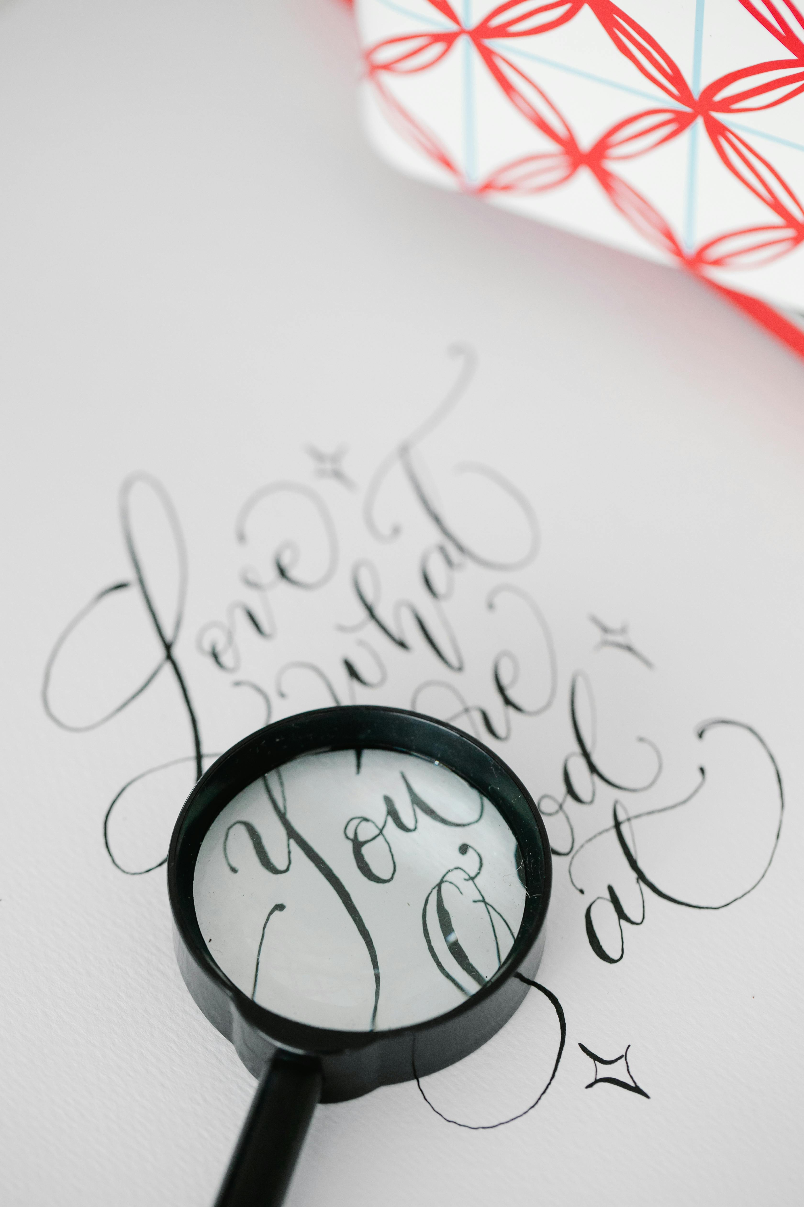 A Magnifier on a Paper Sheet with Calligraphic Letters · Free Stock Photo