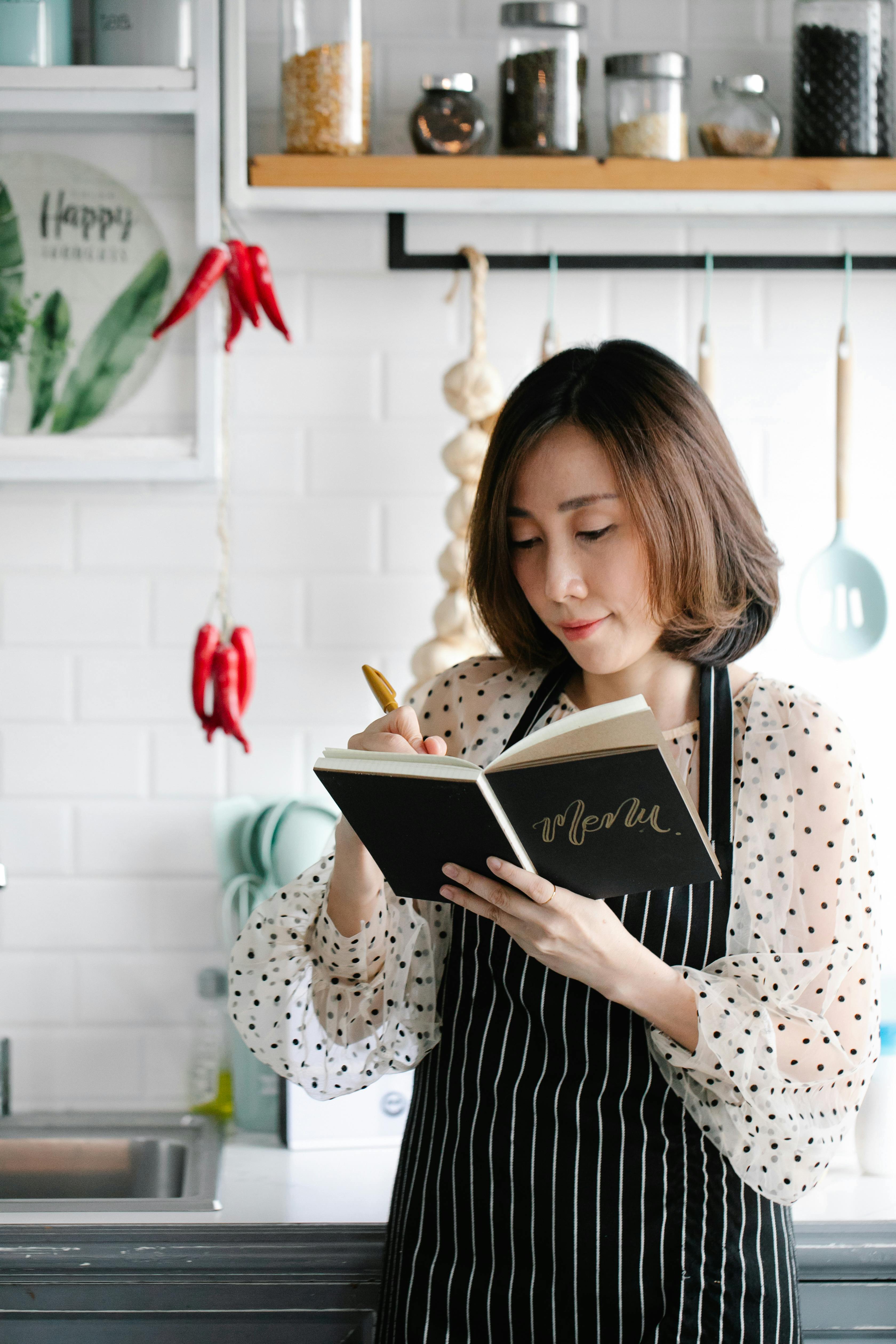 Woman in the Kitchen Writing on a Notebook · Free Stock Photo