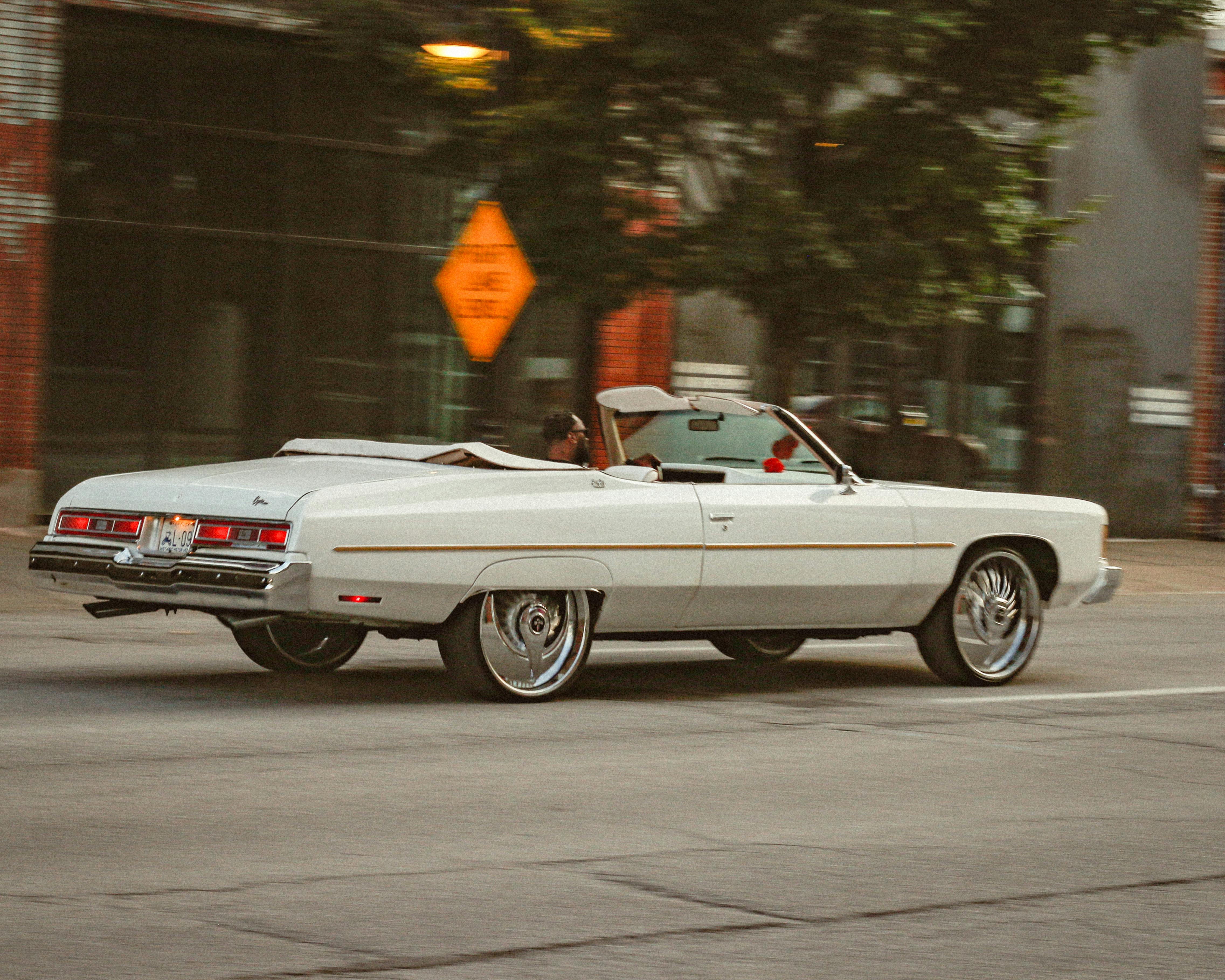 A White Vintage Car Moving on the Road · Free Stock Photo