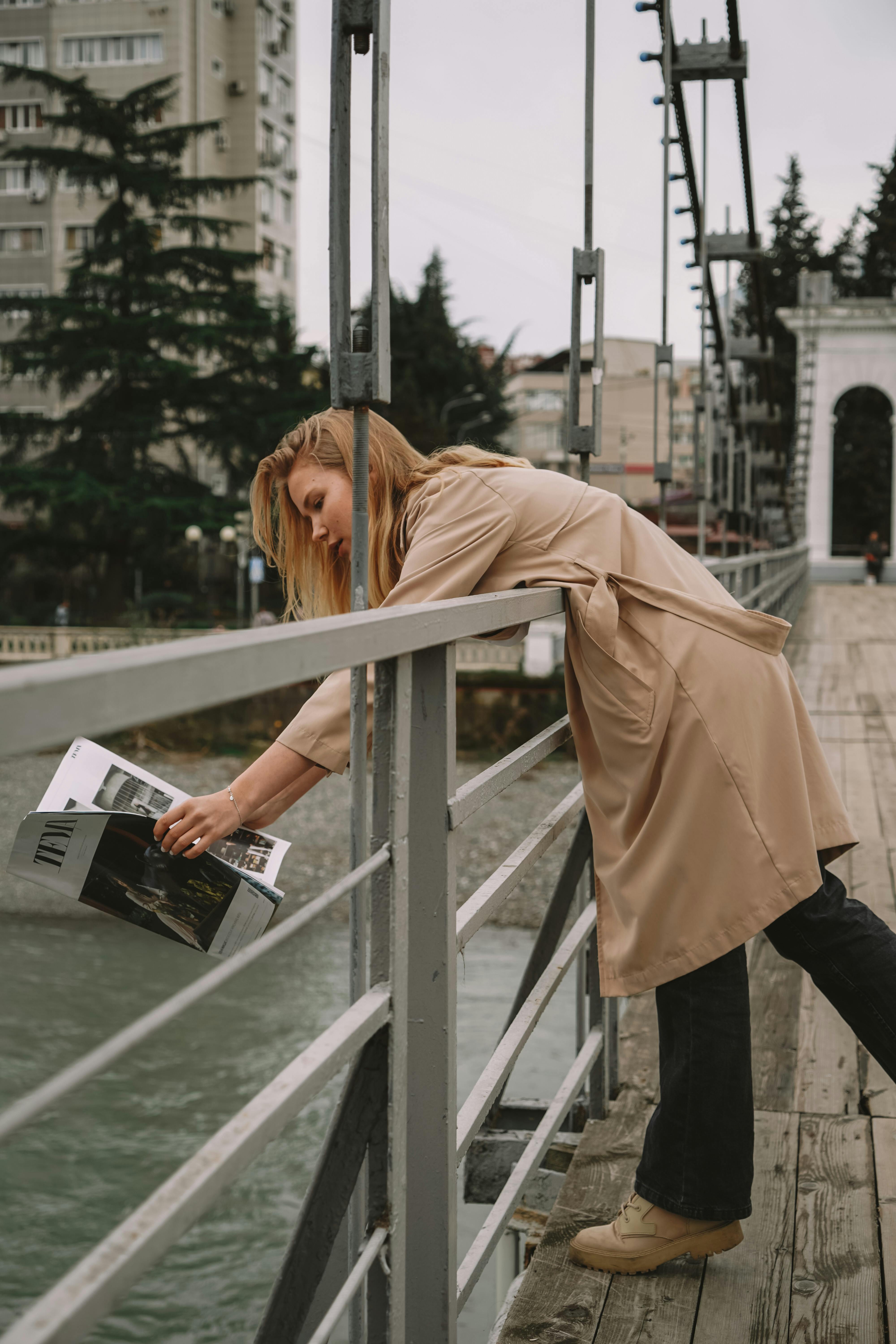 Woman Leaning on Railing While Reading a Magazine · Free Stock Photo
