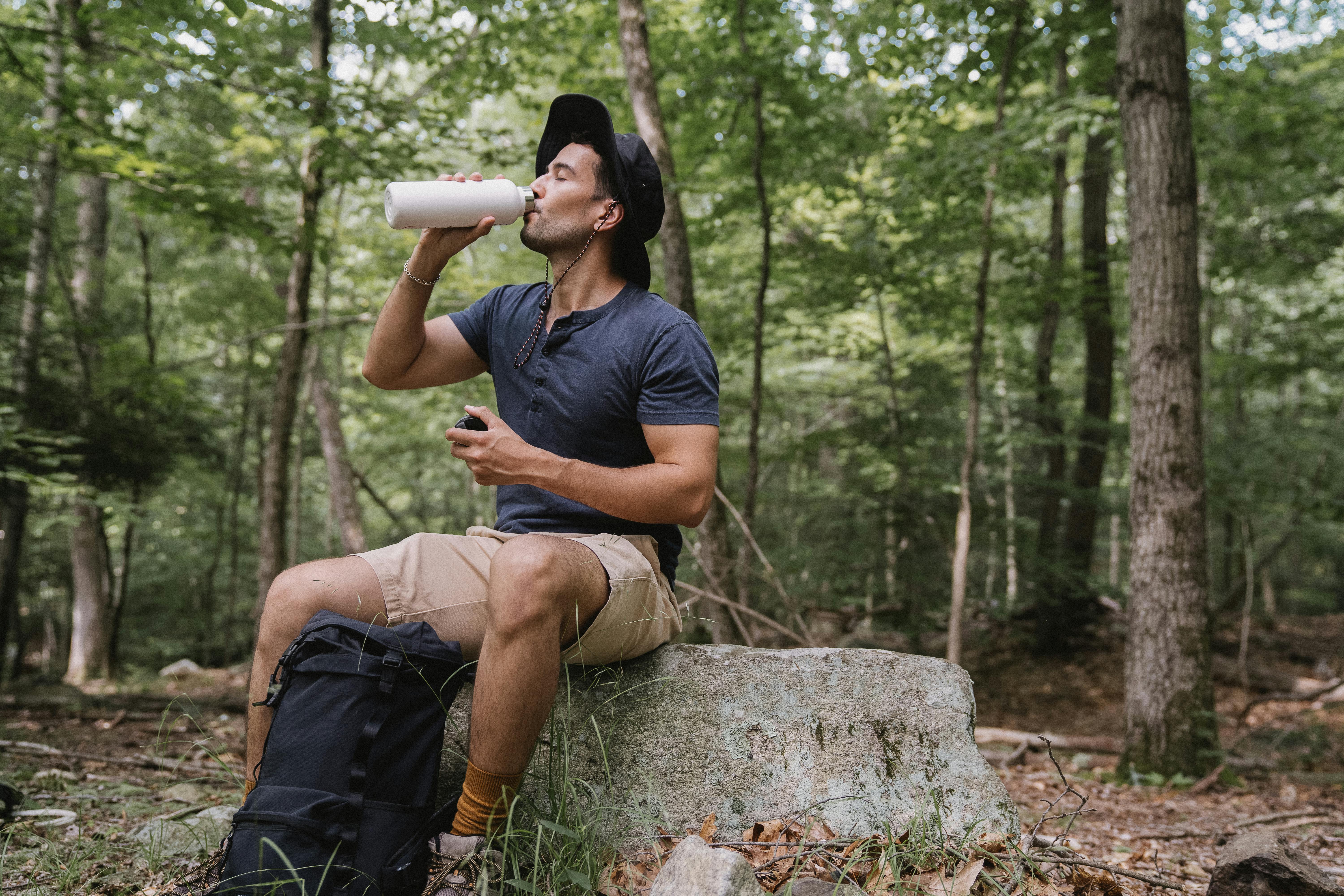 Man Sitting on a Rock Drinking · Free Stock Photo