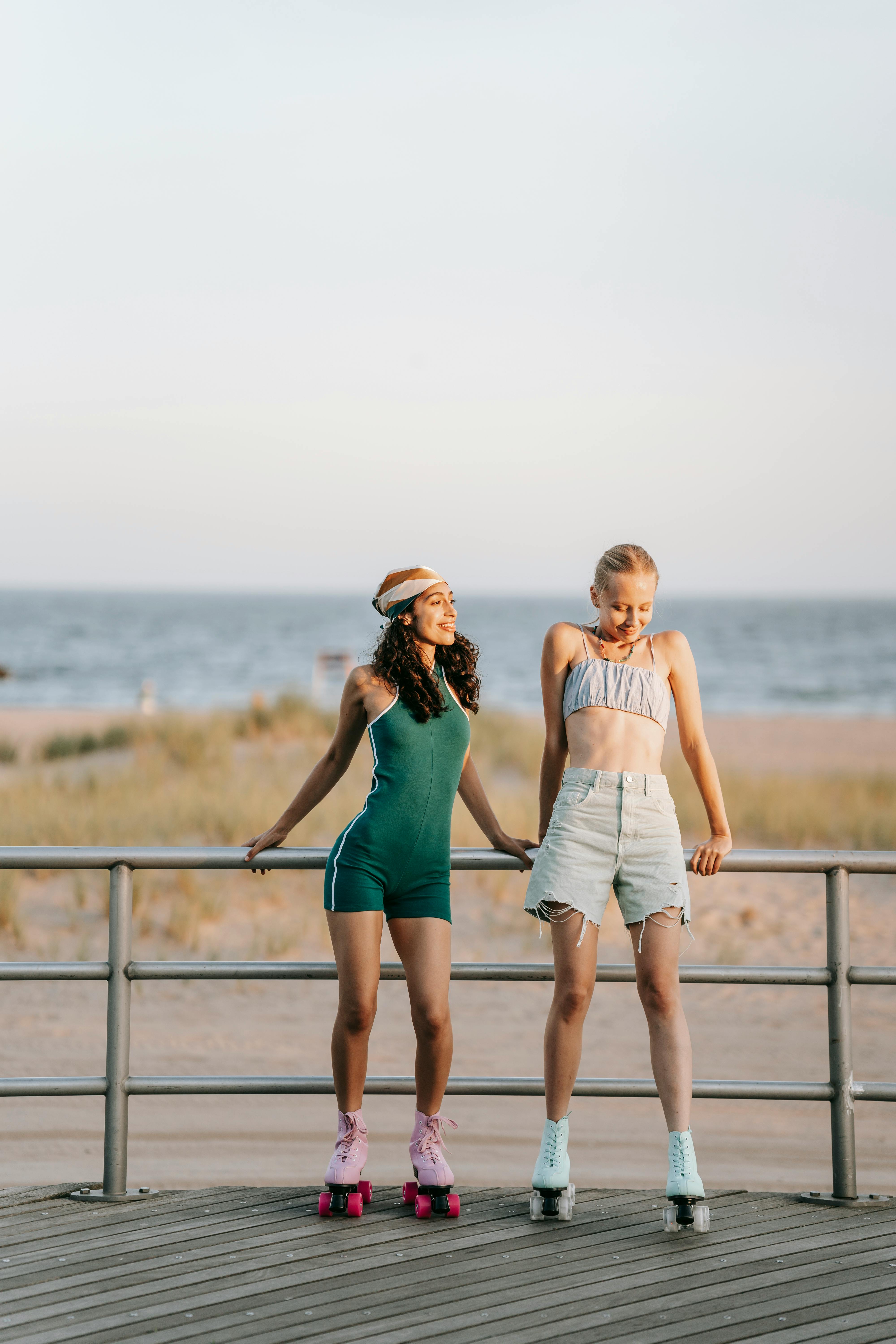 Two Women in Roller Skates Standing Near a Railing · Free Stock Photo