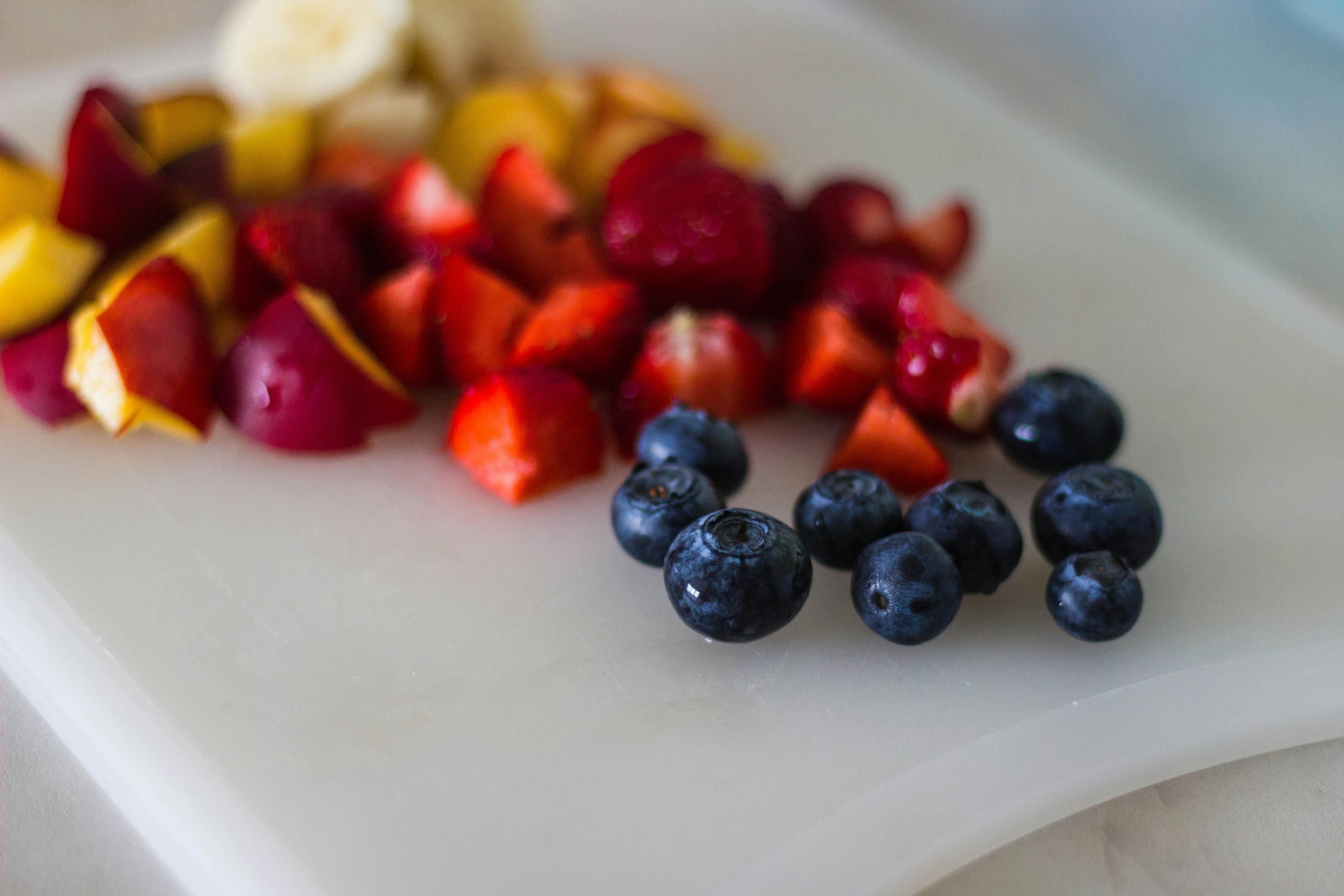 Black Berries With Sliced Fruits on White Plate · Free Stock Photo