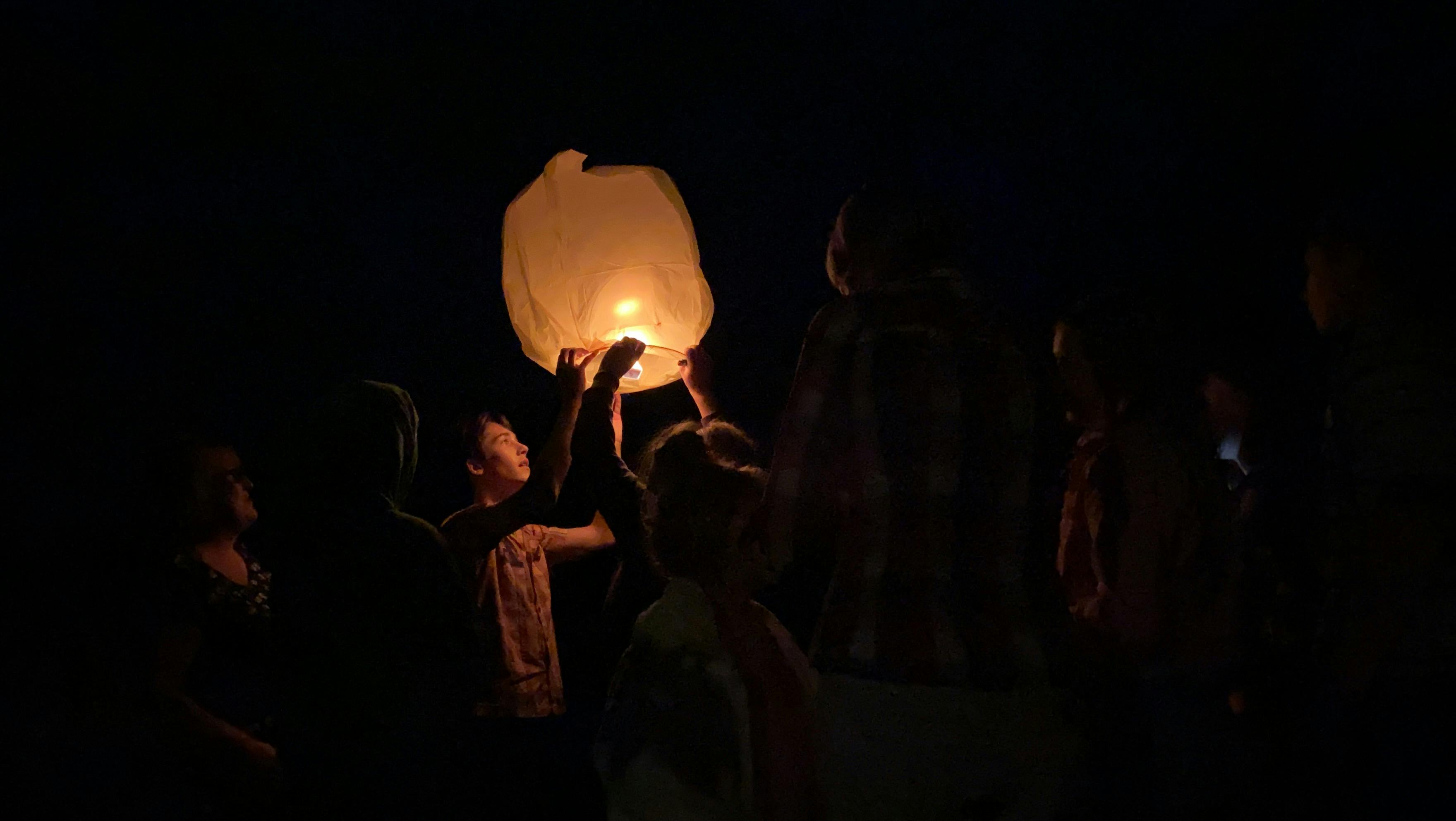 People Lighting Up a Sky Lantern in the Dark · Free Stock Photo
