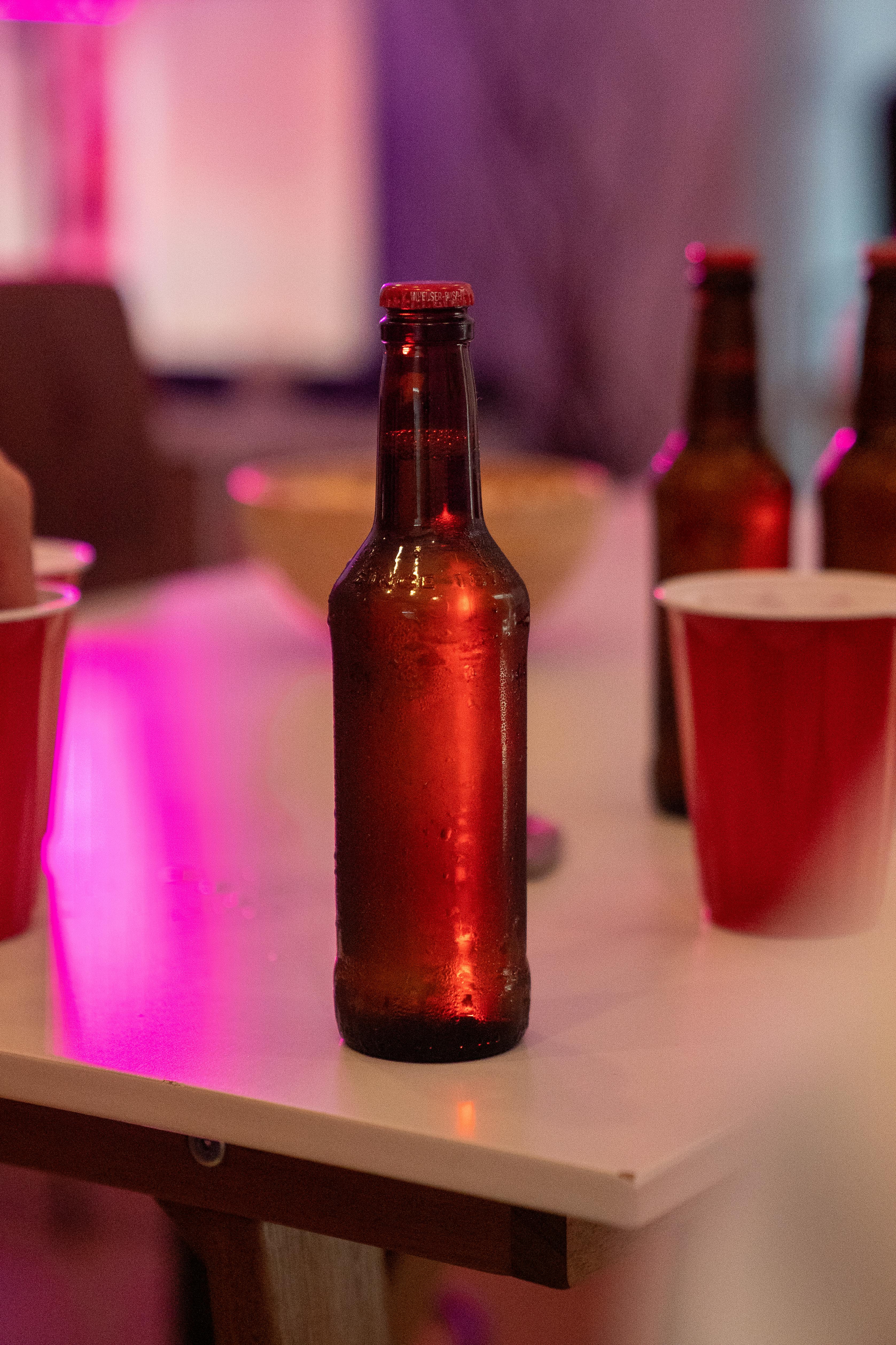 Alcoholic Bottles and Red Cups on White Table · Free Stock Photo