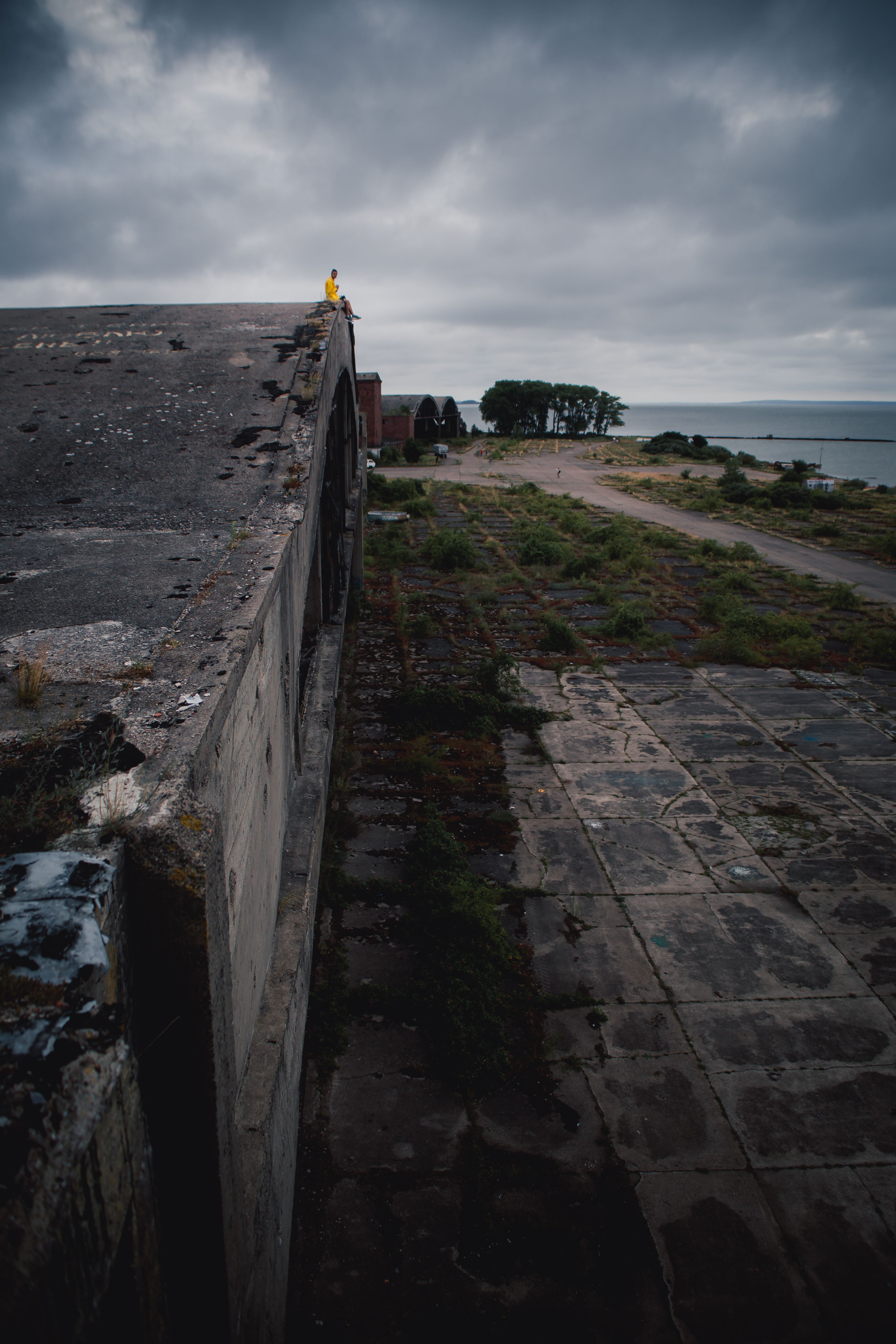 Person Sitting on Roof on Building on Sea Shore · Free Stock Photo