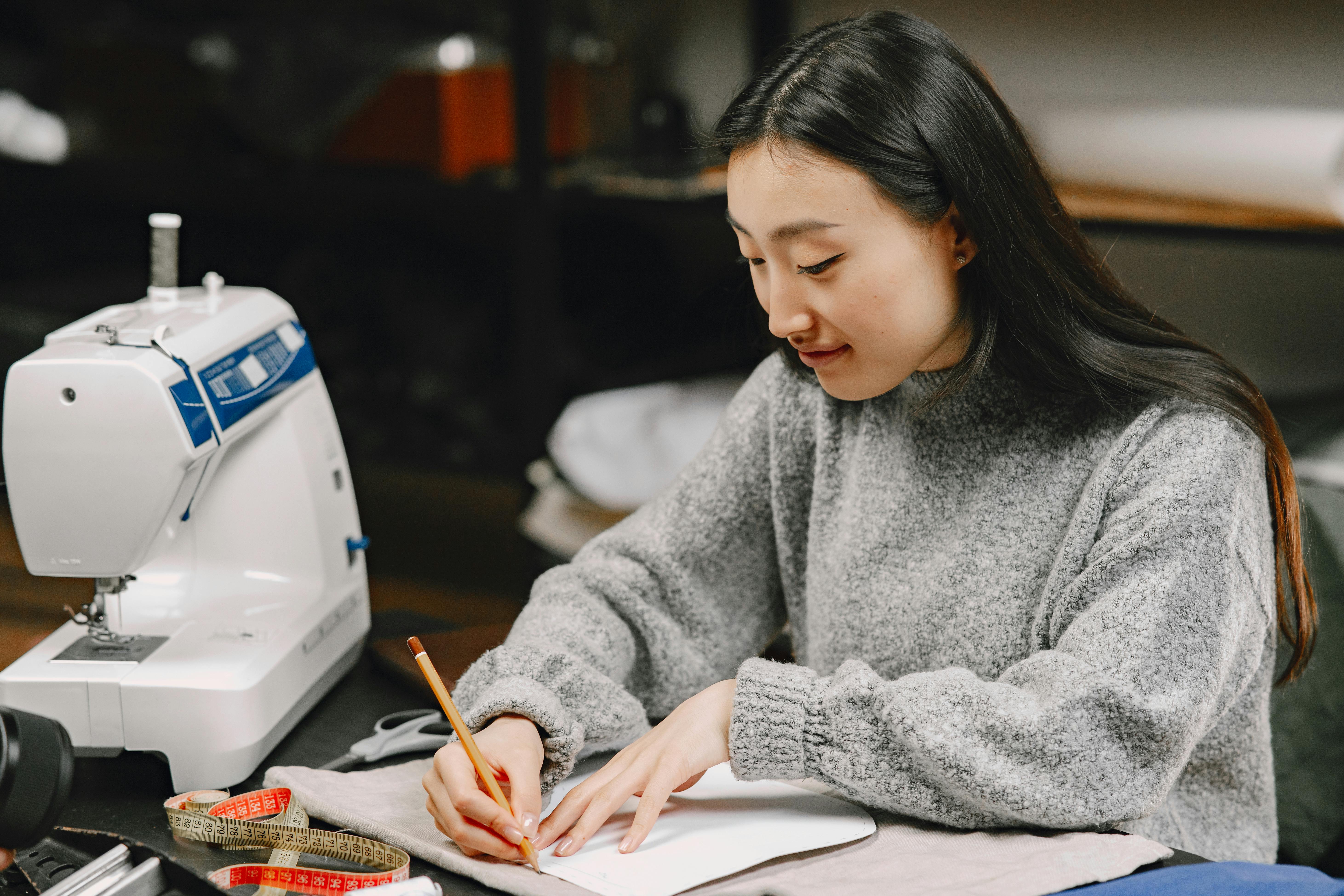 A Woman in Gray Sweater Making Patterns using a Fabric · Free Stock Photo