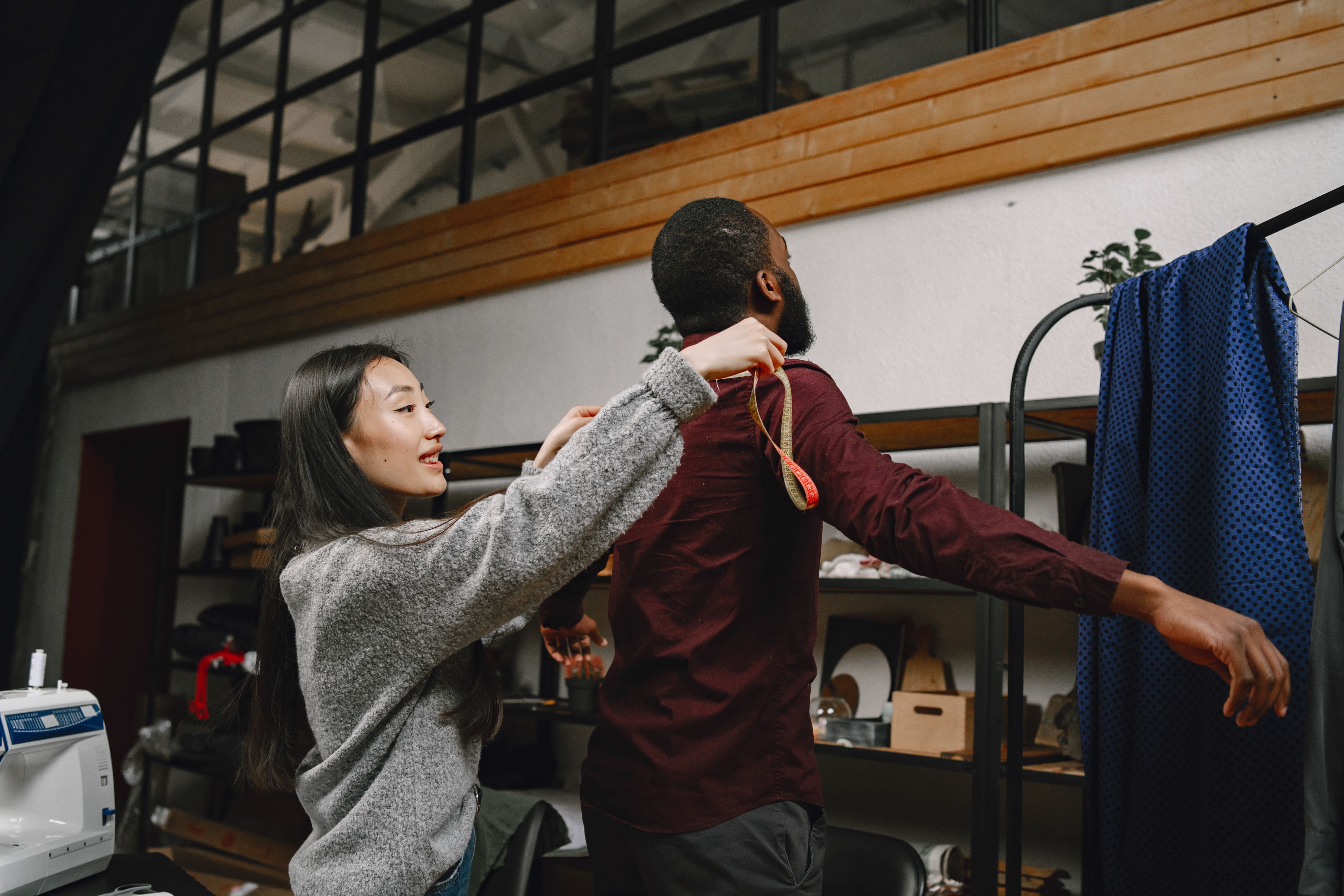 A Woman in Sweater Measuring a Man's Shoulder Using a Measuring Tape ...