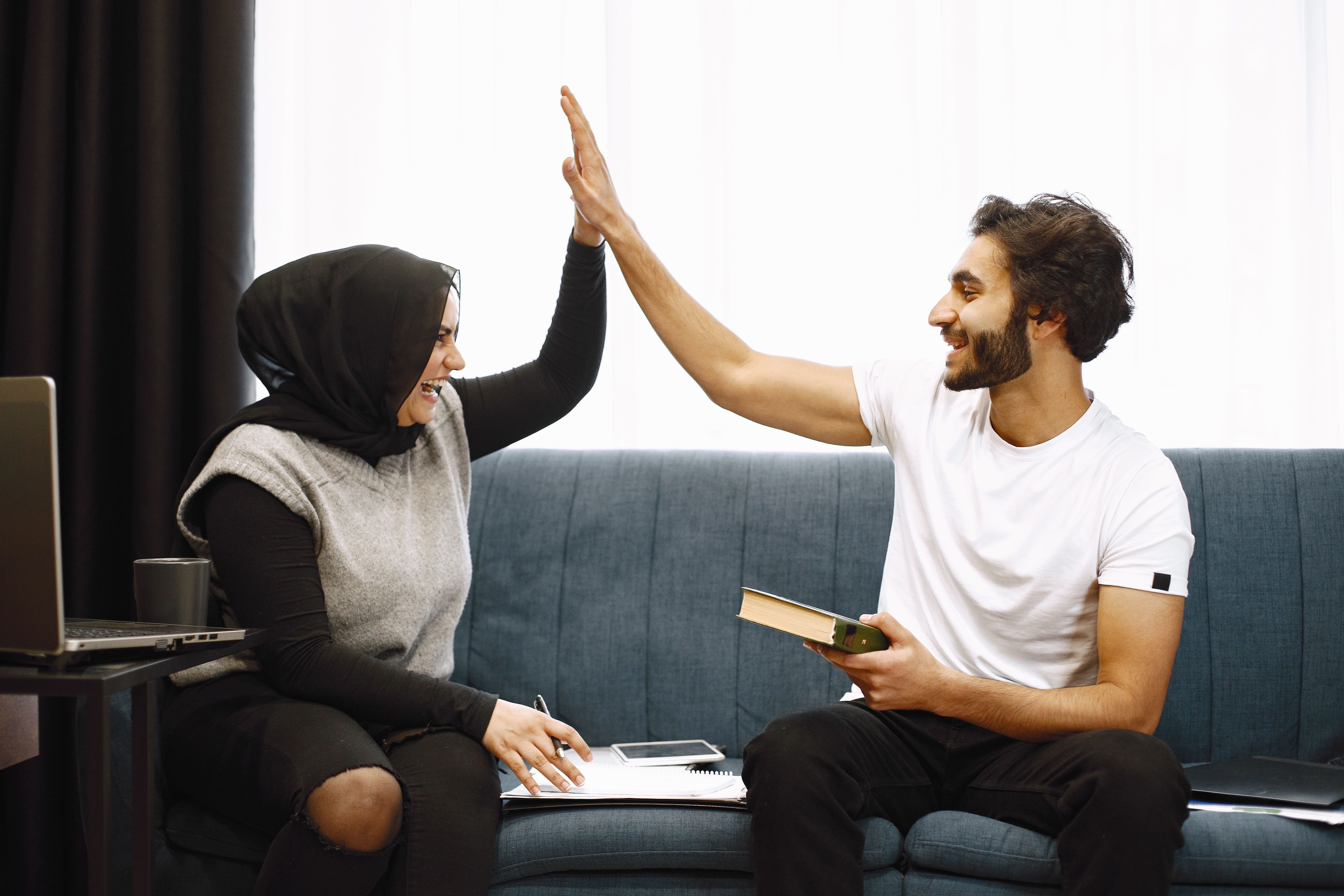 Two Young People High-Fiving on a Sofa · Free Stock Photo