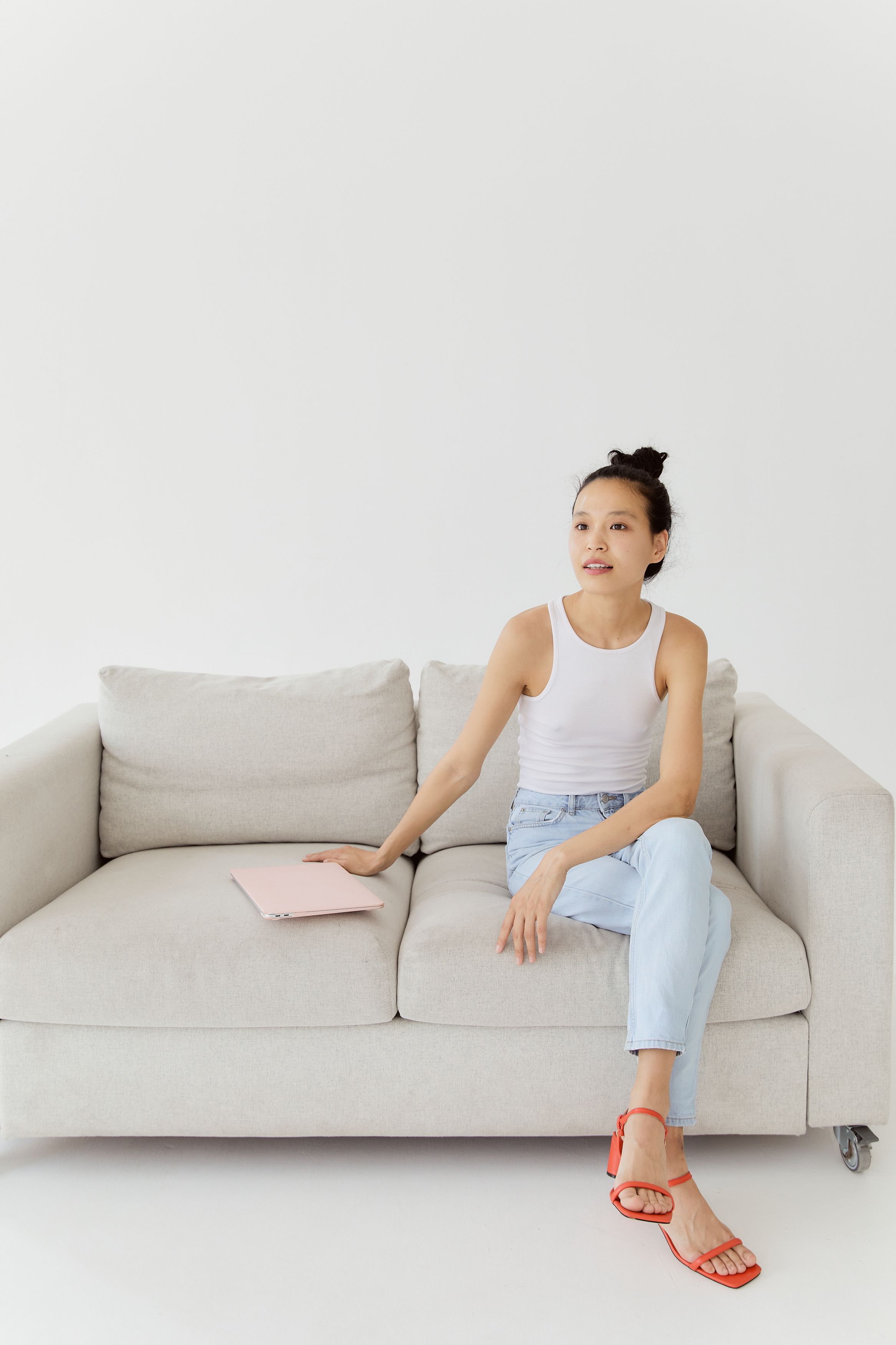 Woman in White Tank Top Sitting on Gray Couch · Free Stock Photo