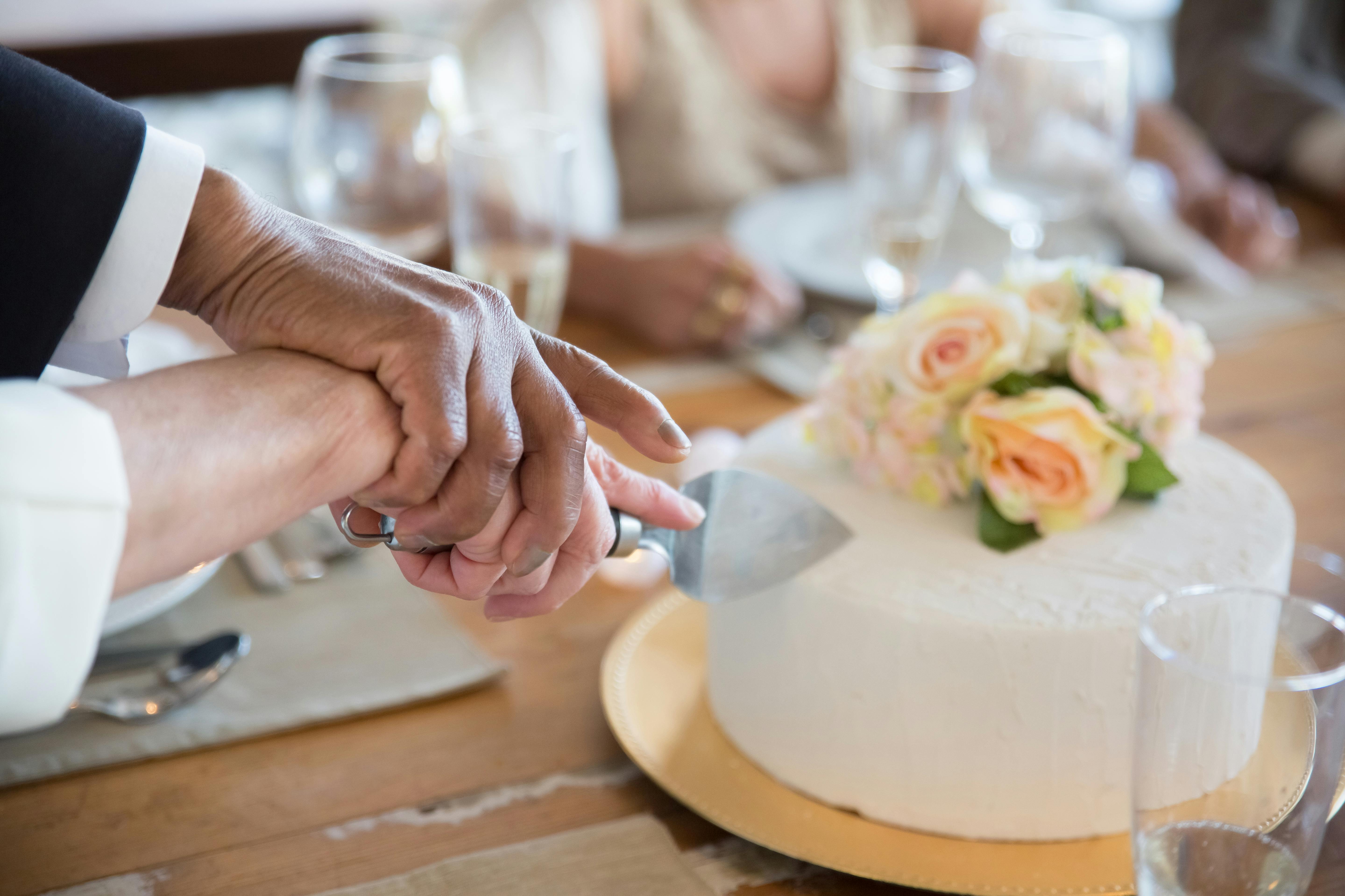 Man and Woman Holding Hands While Slicing Cake · Free Stock Photo