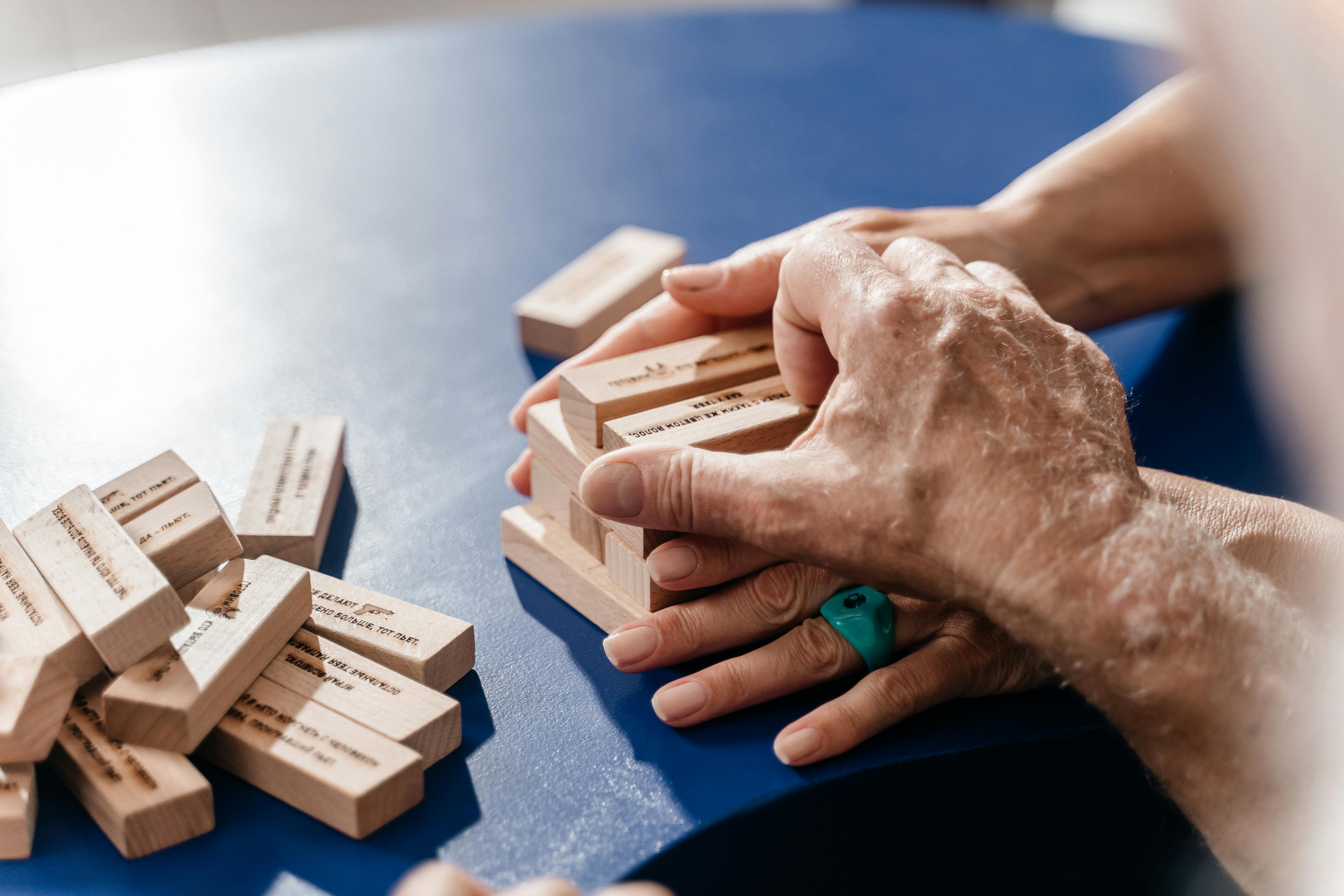 Hands Playing with Wooden Blocks on a Blue Table · Free Stock Photo