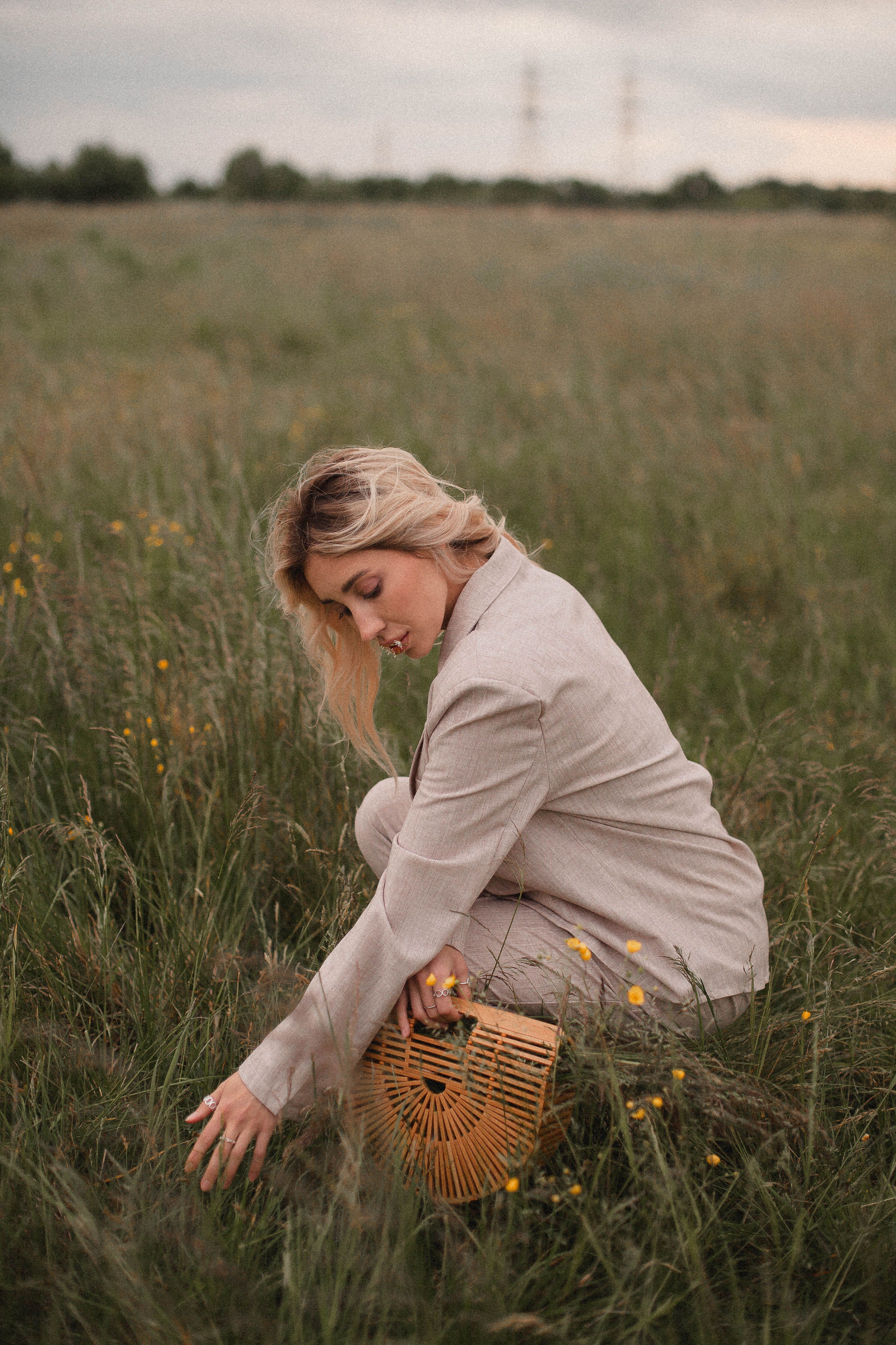 A Woman Crouching on a Grassland · Free Stock Photo