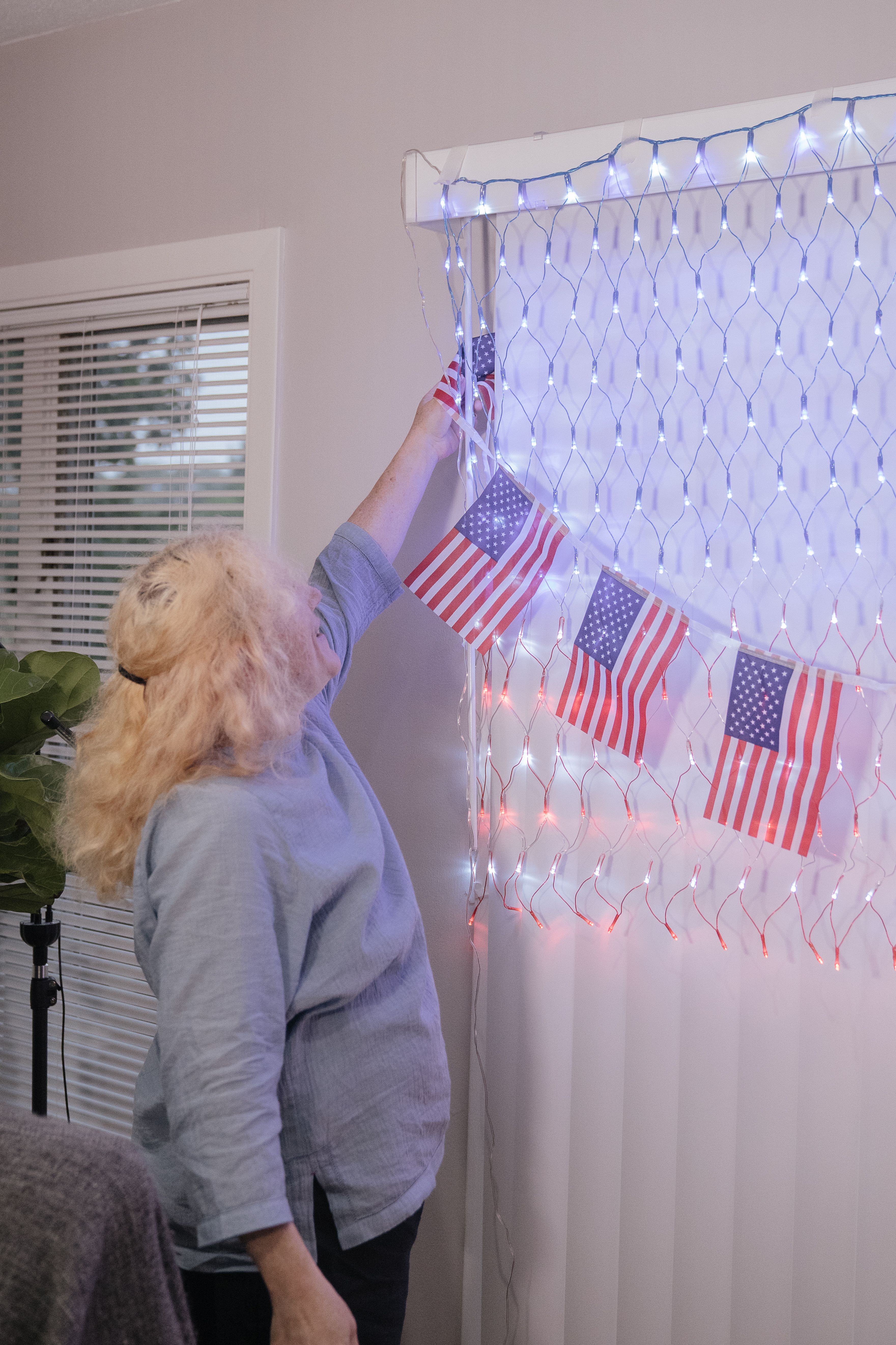 Elderly Person hanging American Flags at a Window · Free Stock Photo